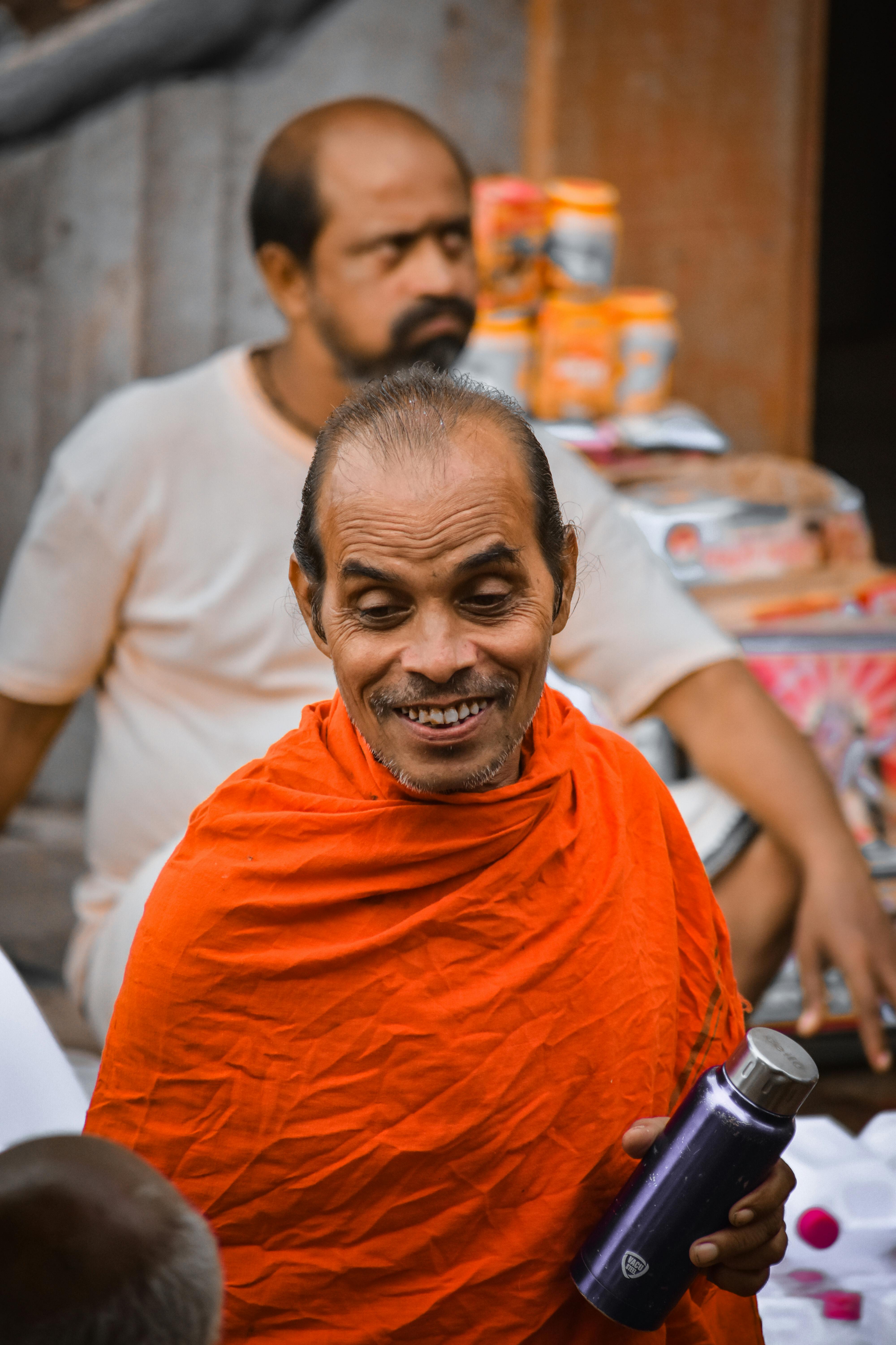Smiling Buddhist Monk with a Thermos in the Marketplace · Free Stock Photo