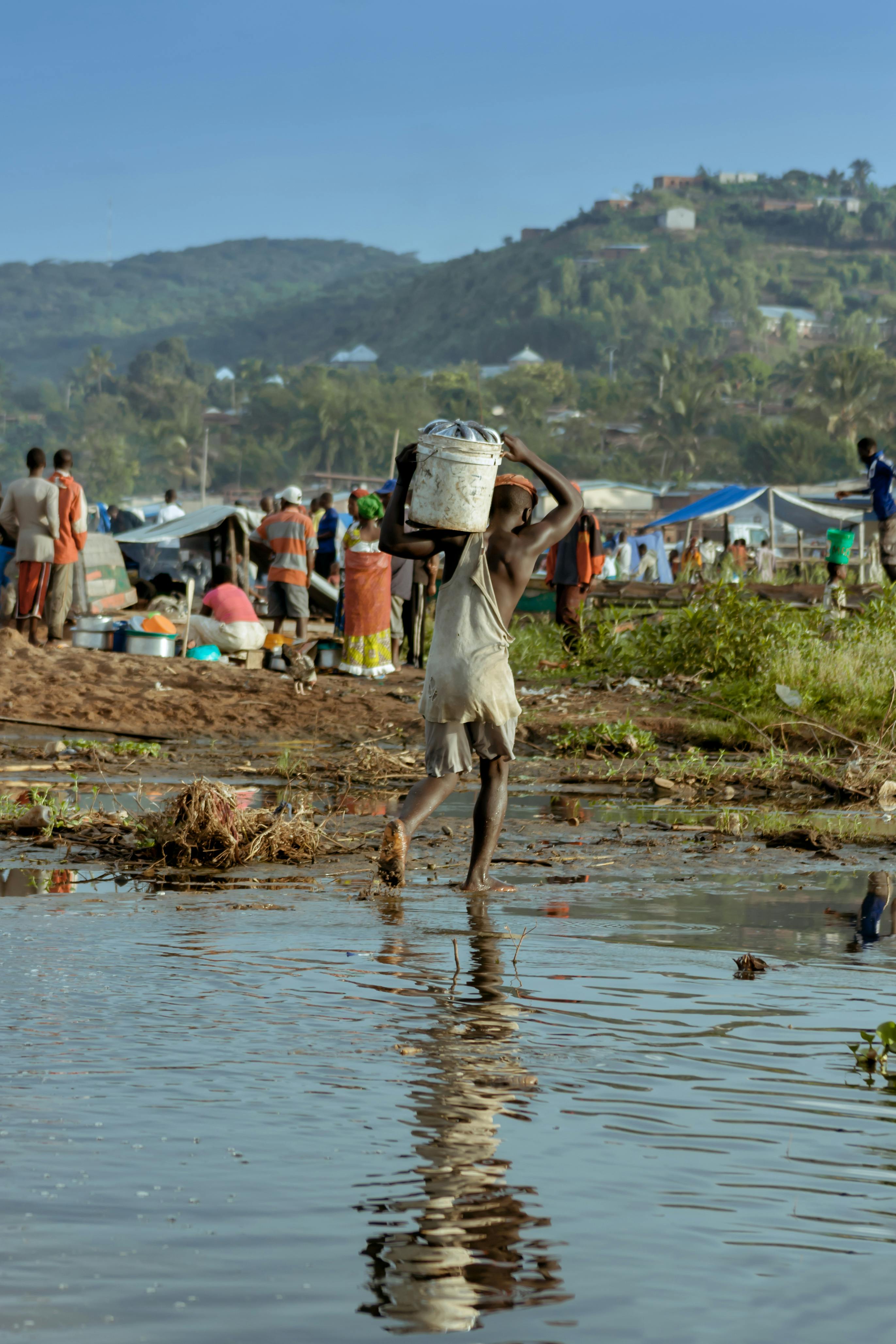 Man Carrying Bucket on Lakeshore · Free Stock Photo