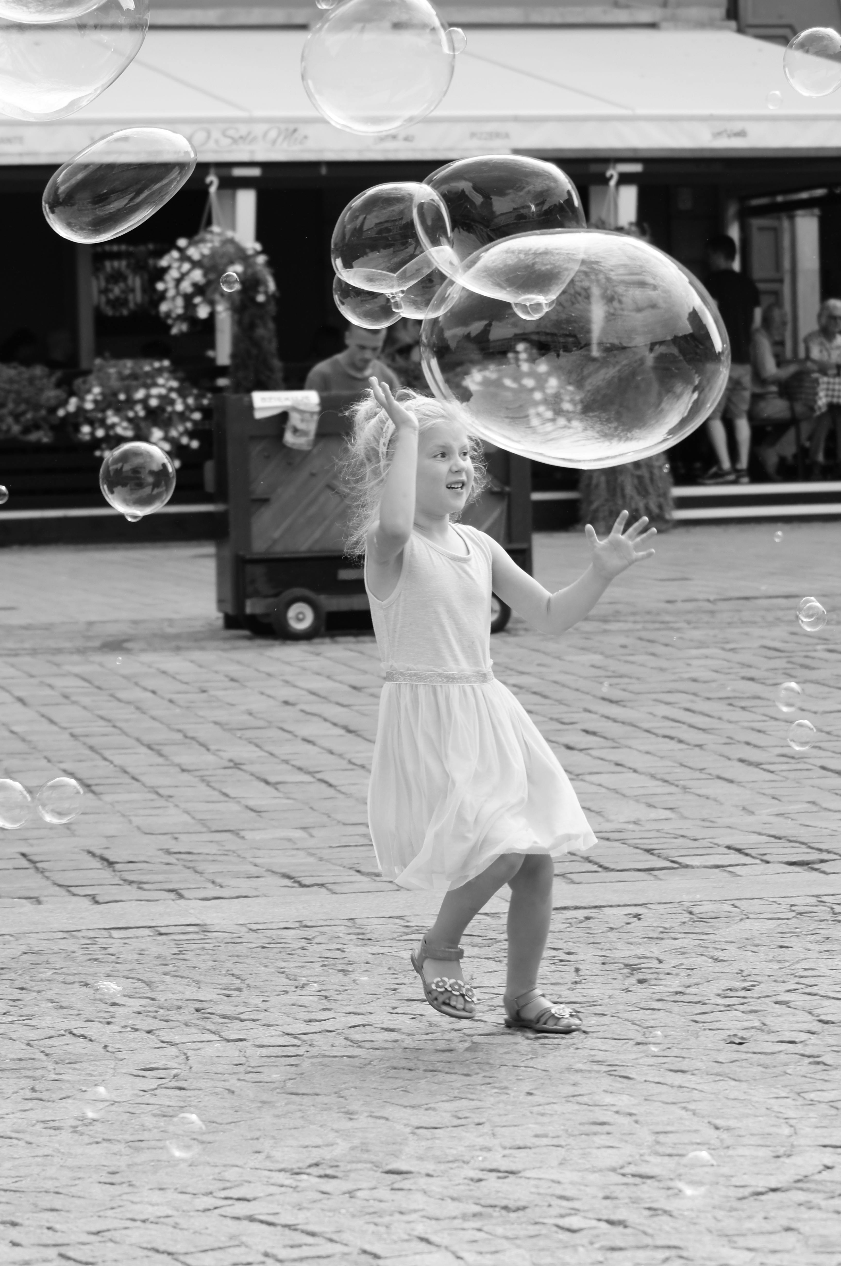 A Little Girl Running among Soap Bubbles on the Pavement · Free Stock Photo