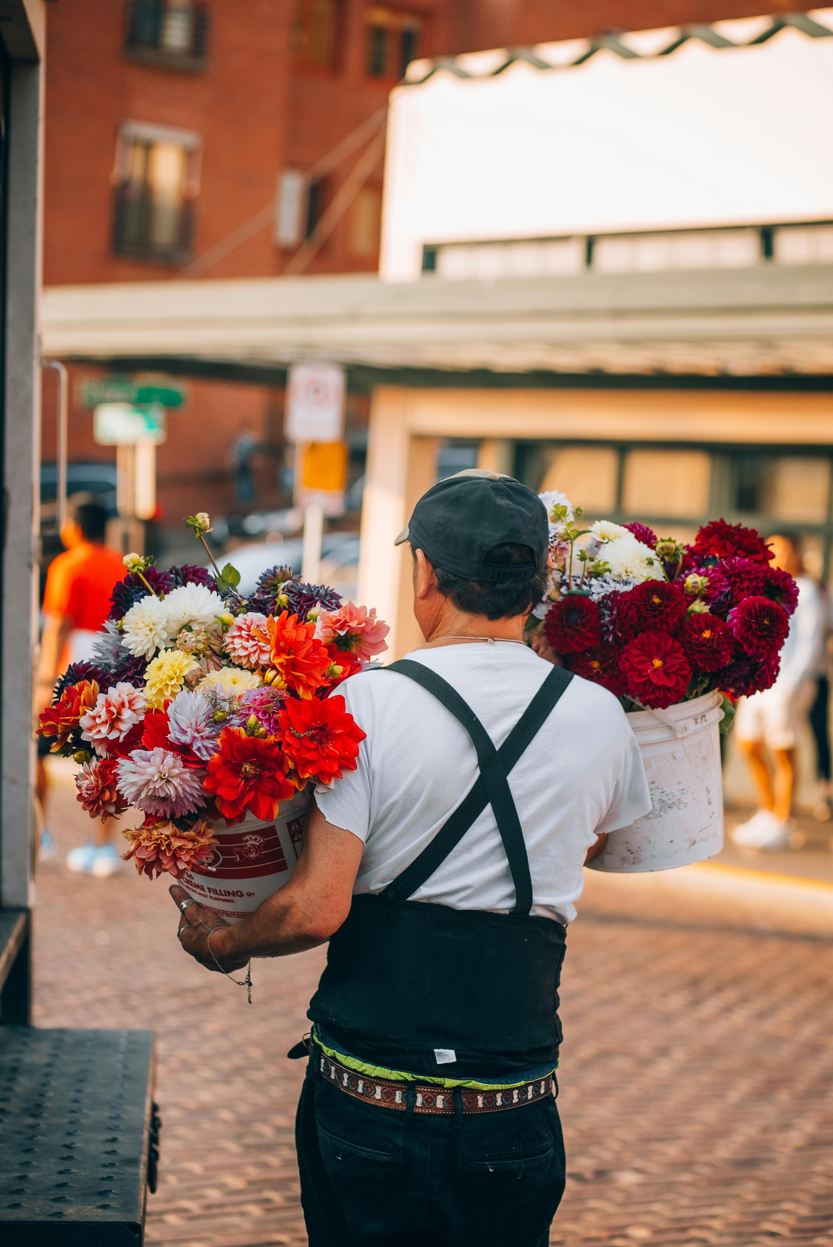 A man carrying flowers on a street · Free Stock Photo