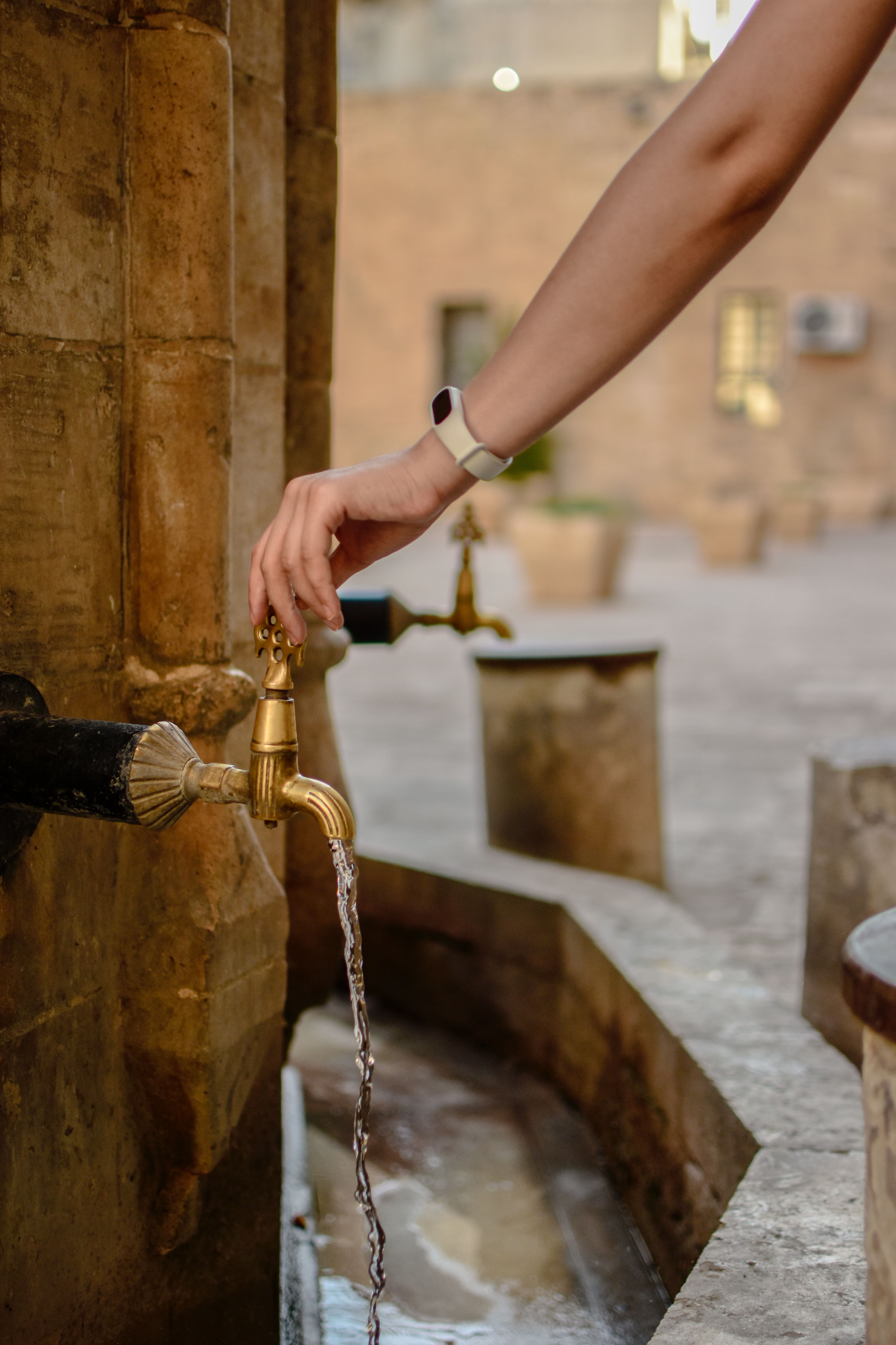 Hand Turning on Faucet of Public Fountain · Free Stock Photo