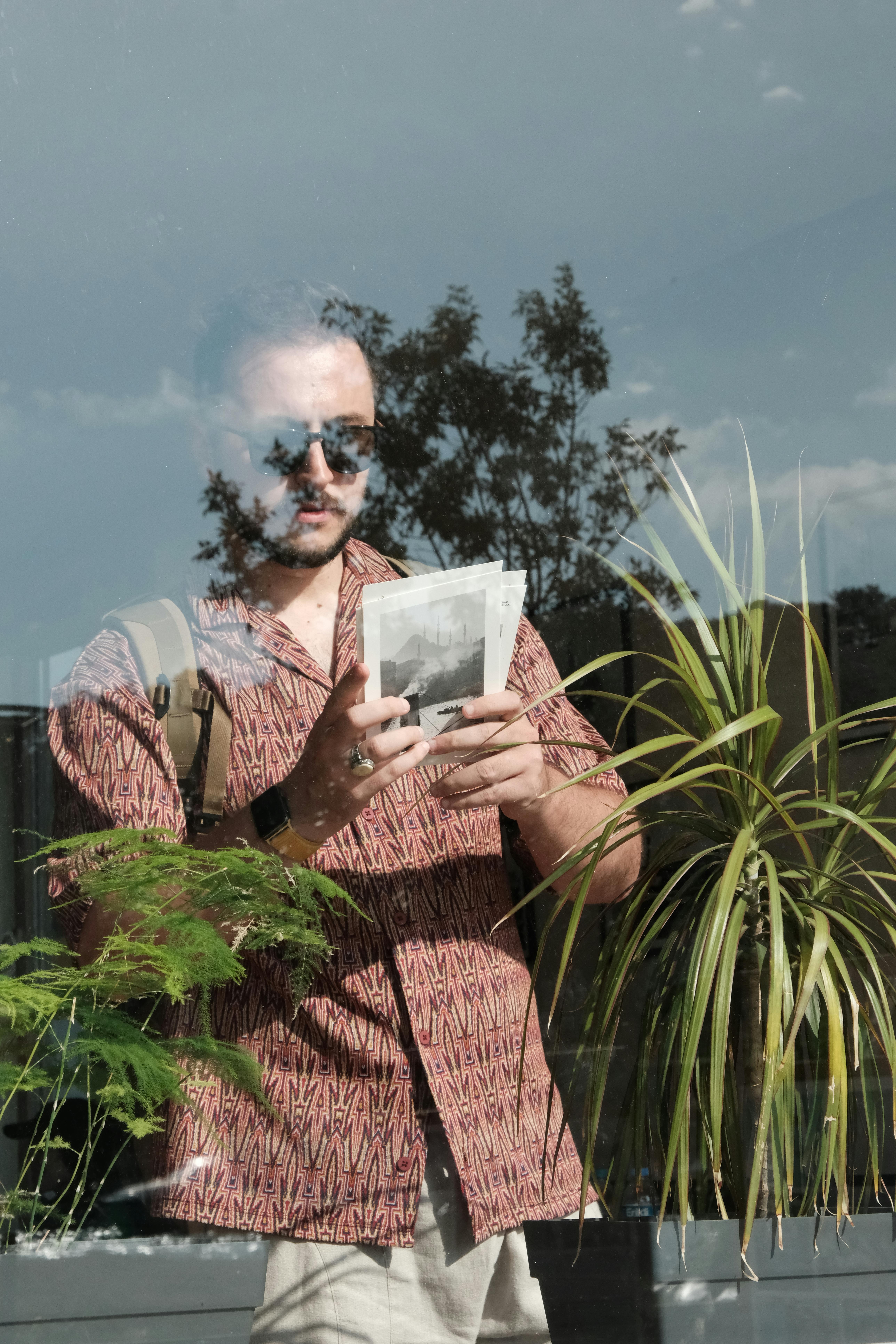 A Reflection in a Window Glass of a Man Looking at Postcards · Free ...