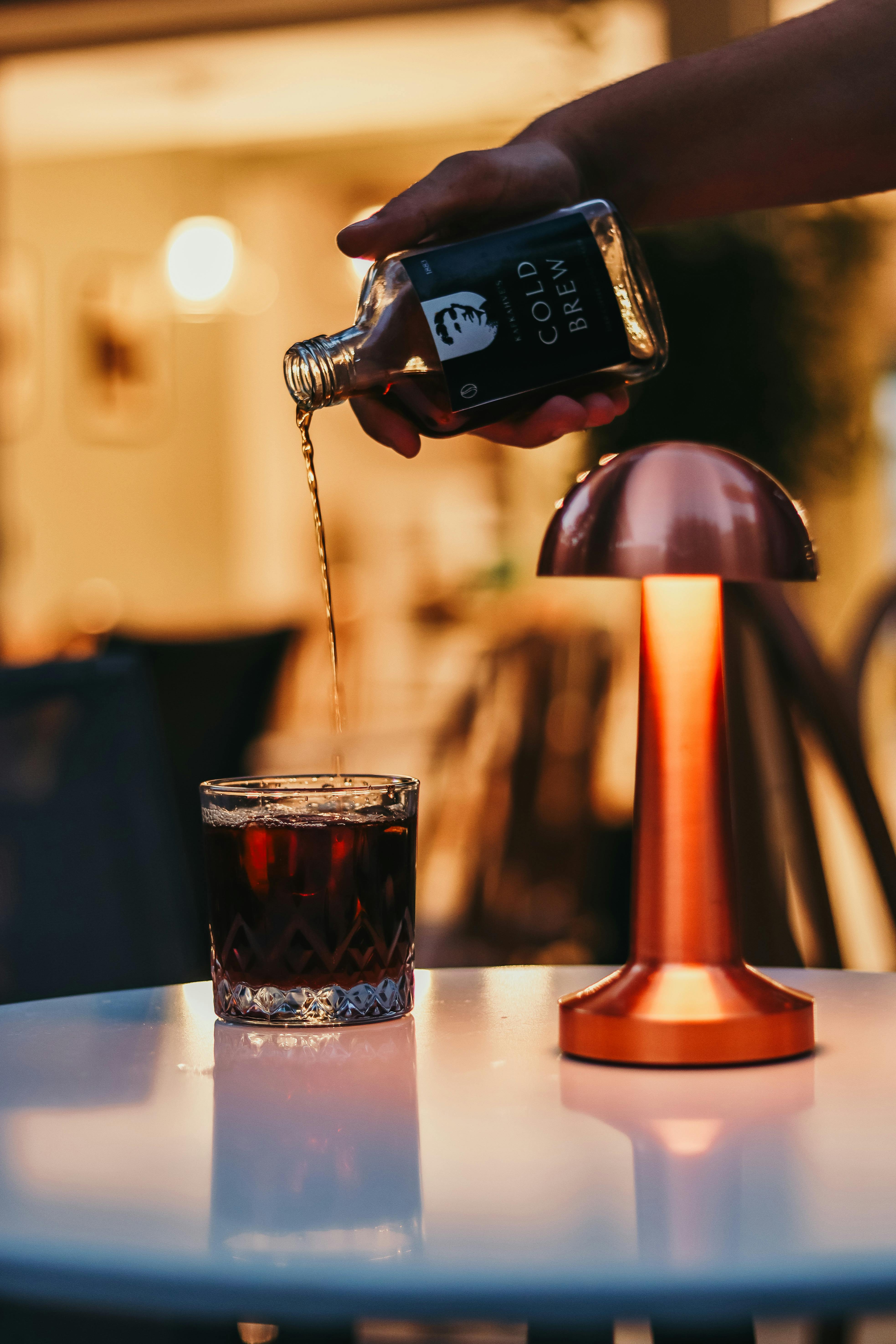 Man Pouring Cold Brew Coffee Drink from a Glass Bottle · Free Stock Photo