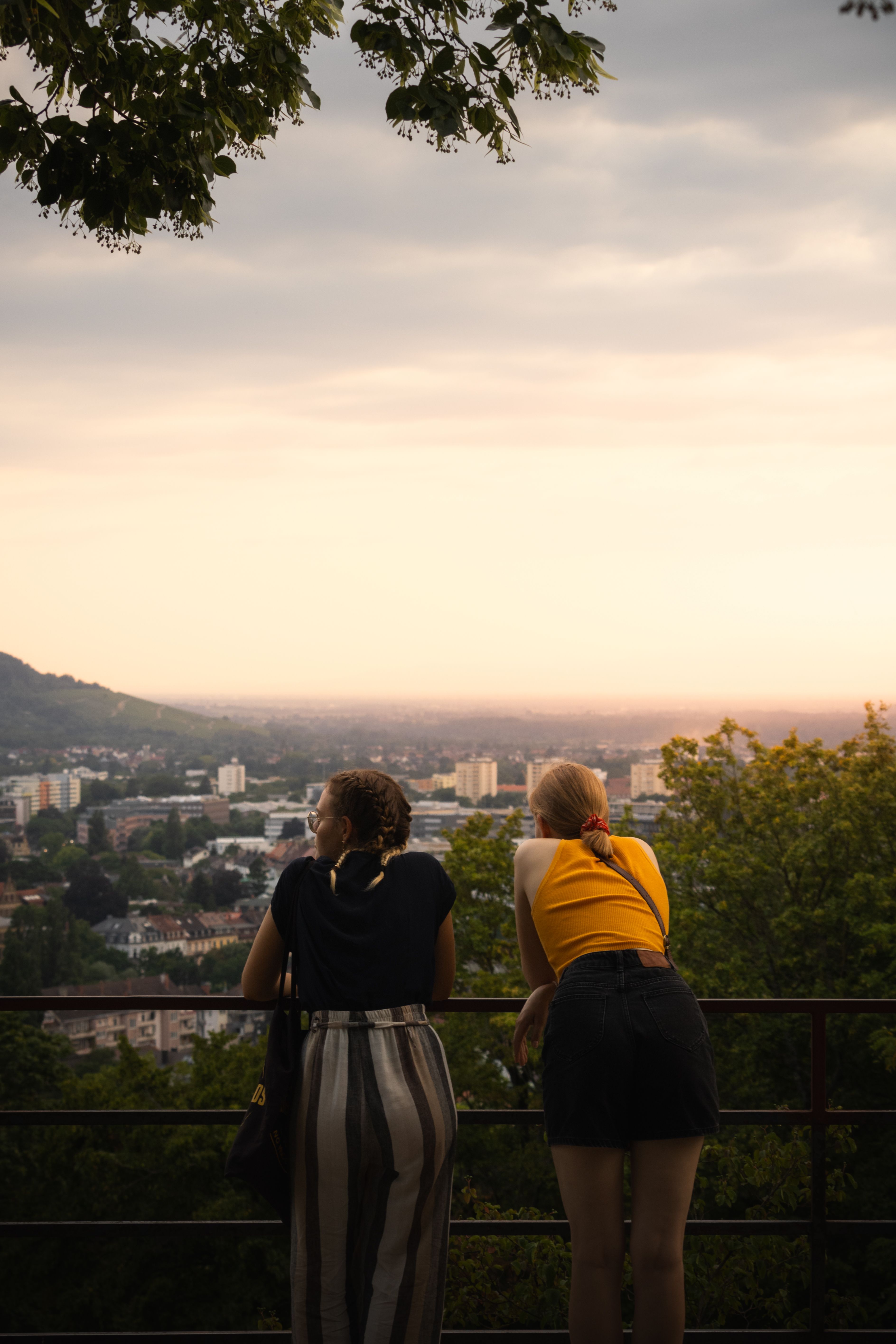 Back View of Women Standing on a Lookout Point overlooking a City ...