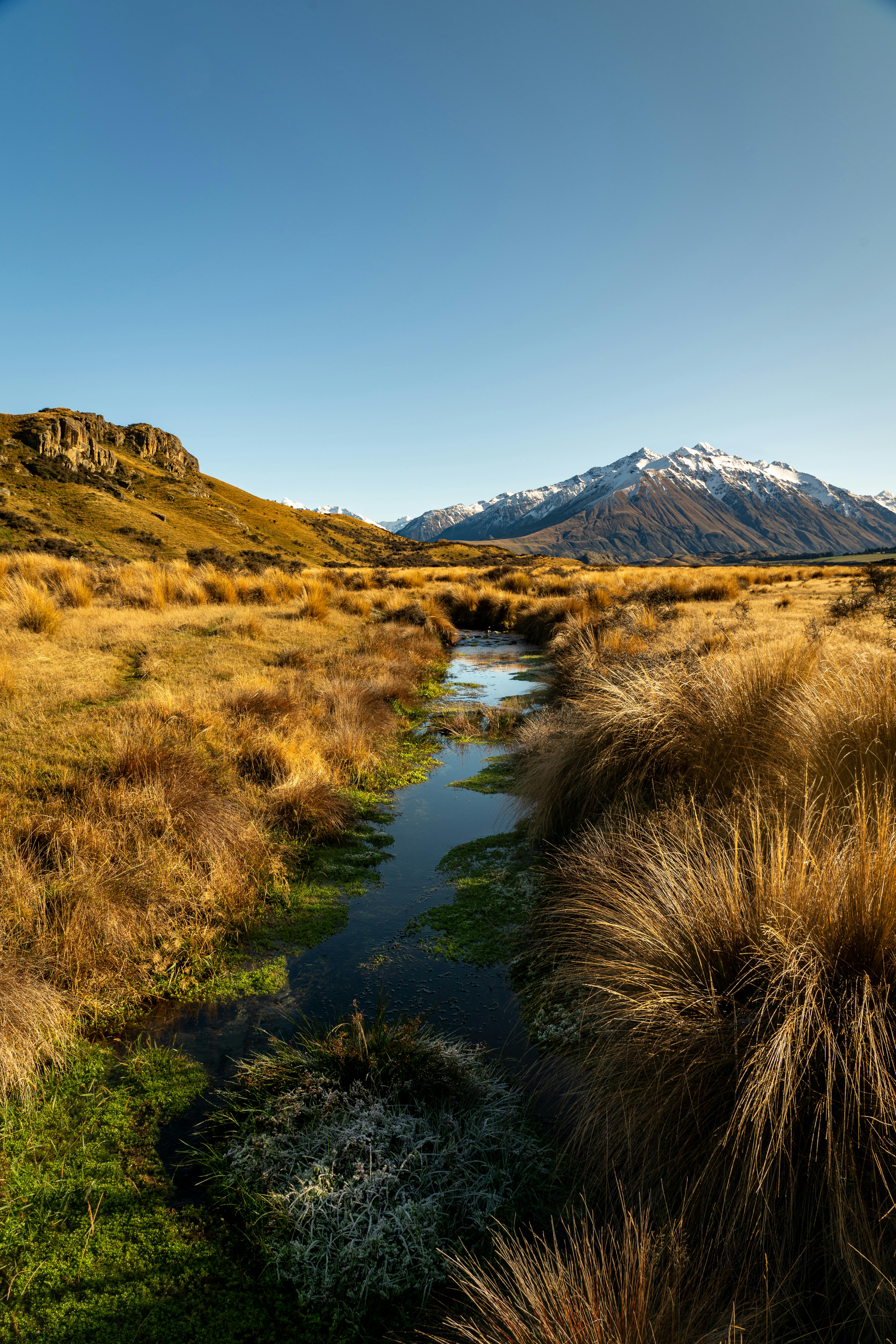 View of a Stream, Grass Field and Mountains in Distance under Blue Sky ...