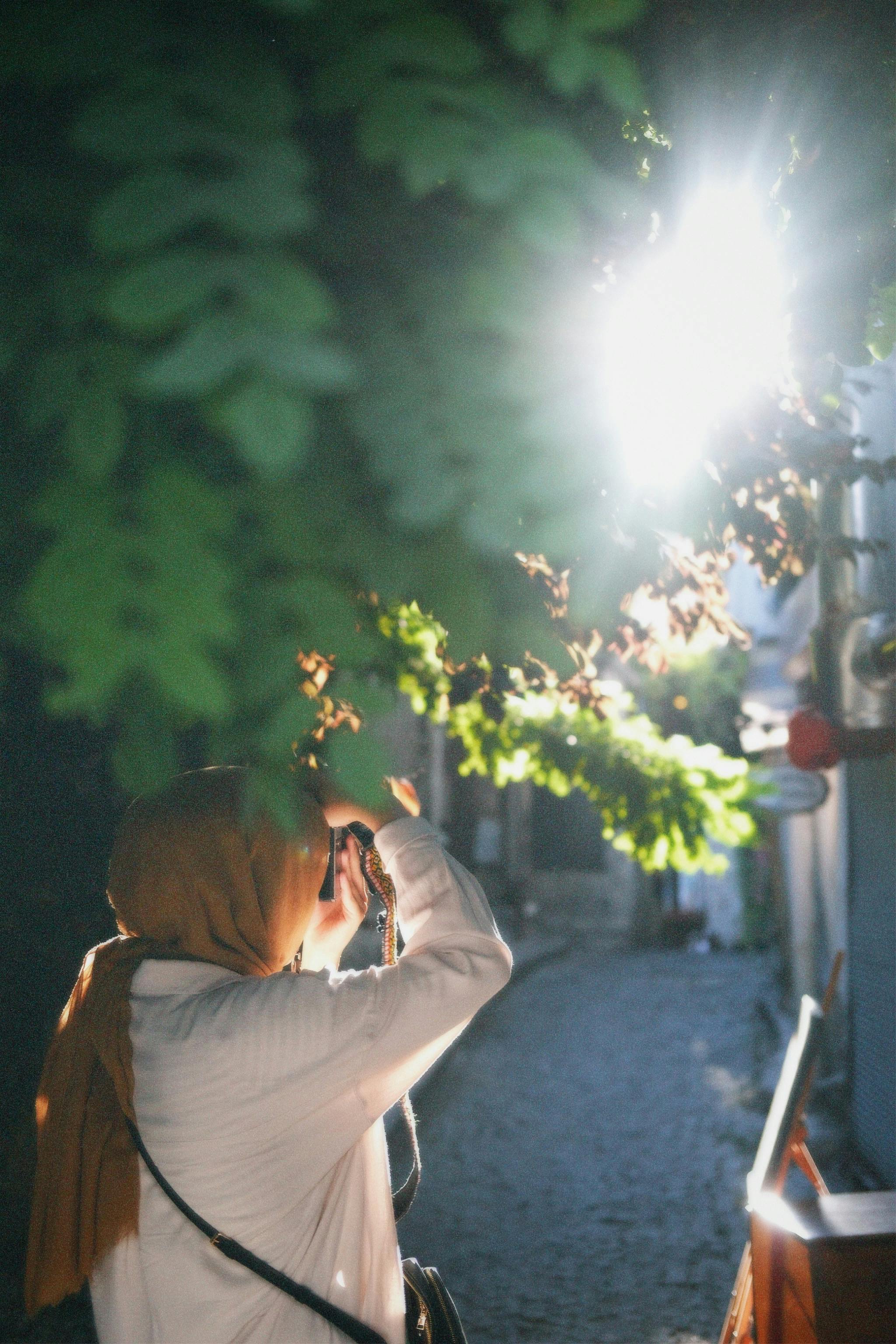 Woman Taking a Photo of the Sunset over a Cobbled Alley Between Houses ...