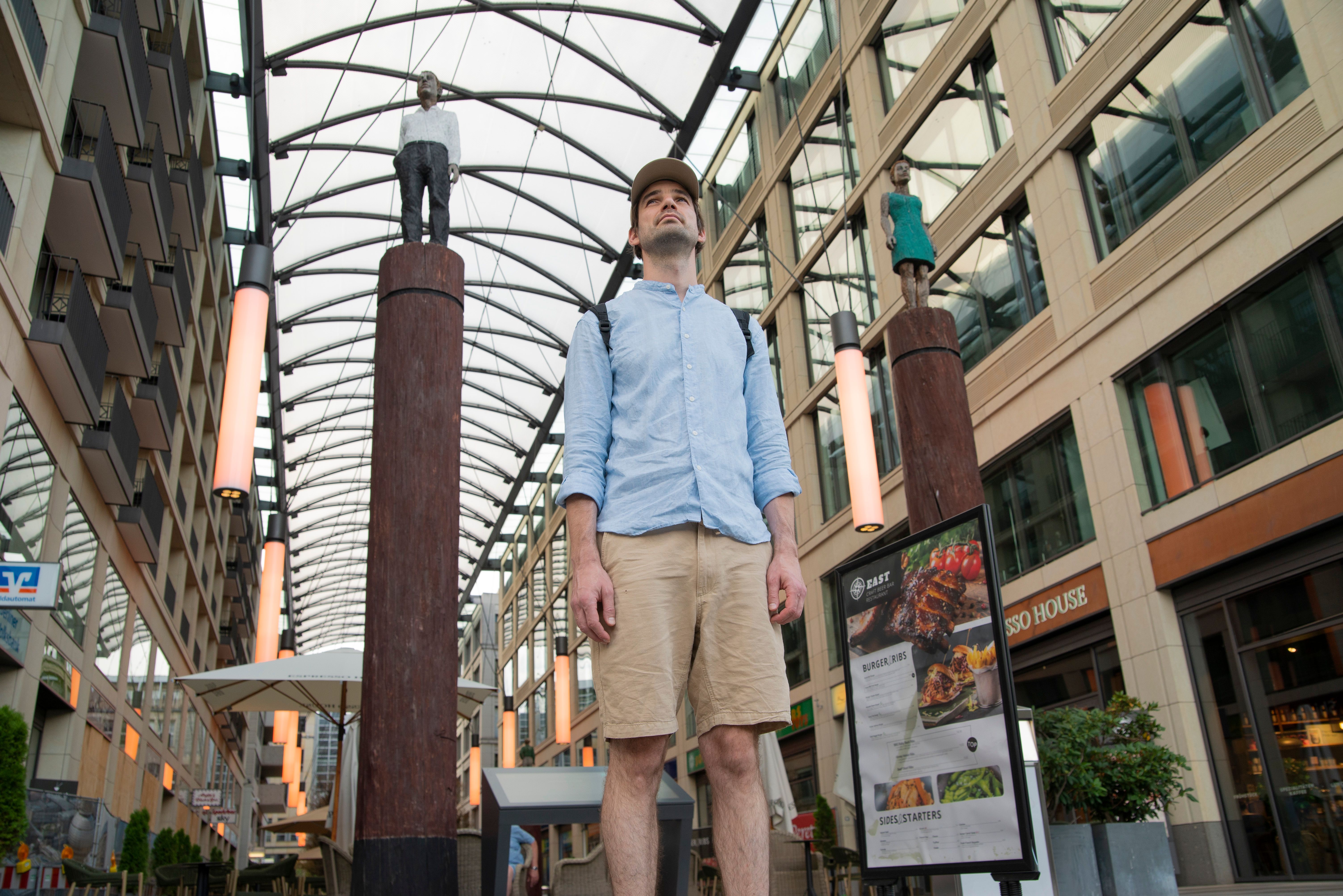 Man Standing under Sculpture · Free Stock Photo