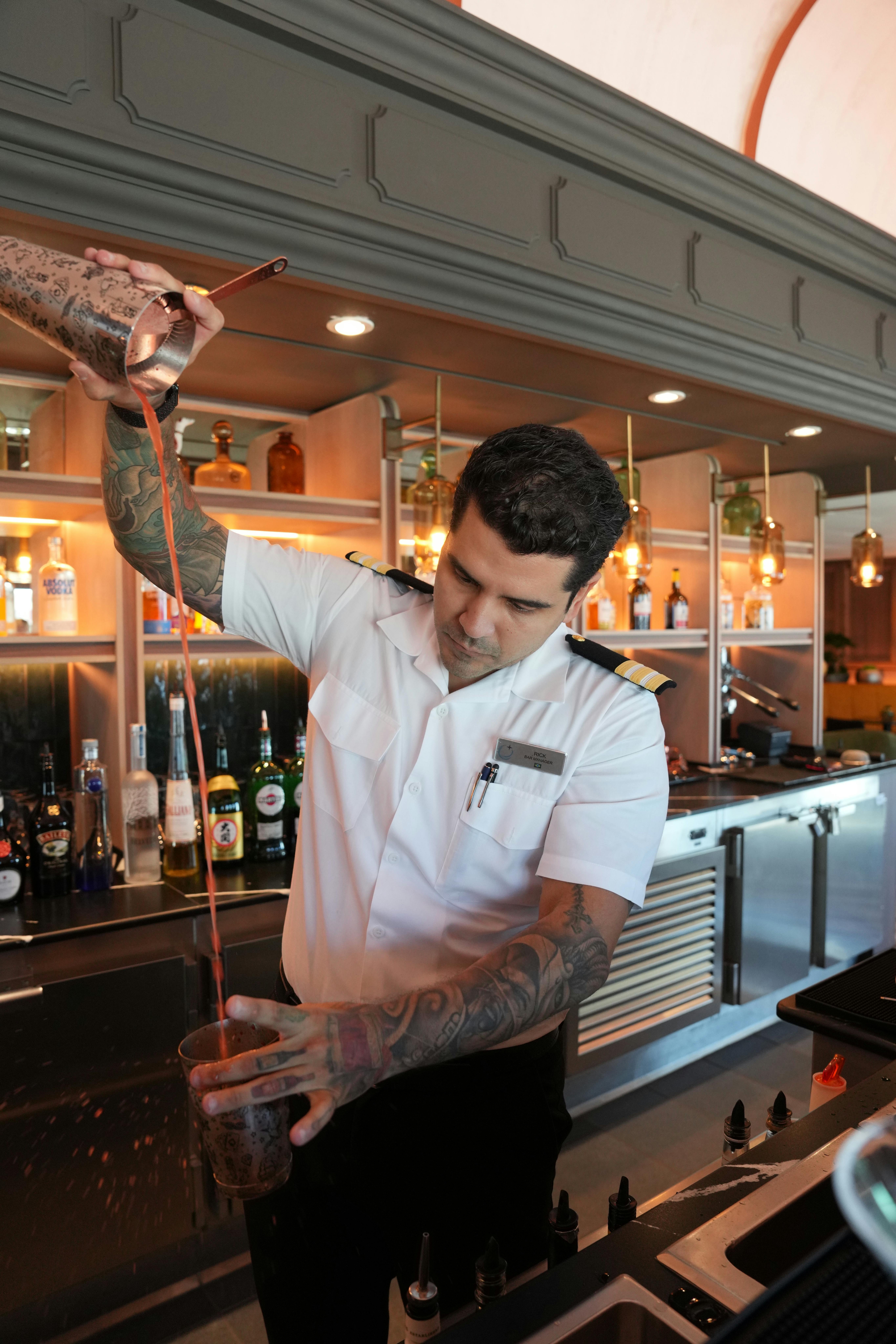 Bartender in Marine Suit Pouring Cocktail into Glass · Free Stock Photo