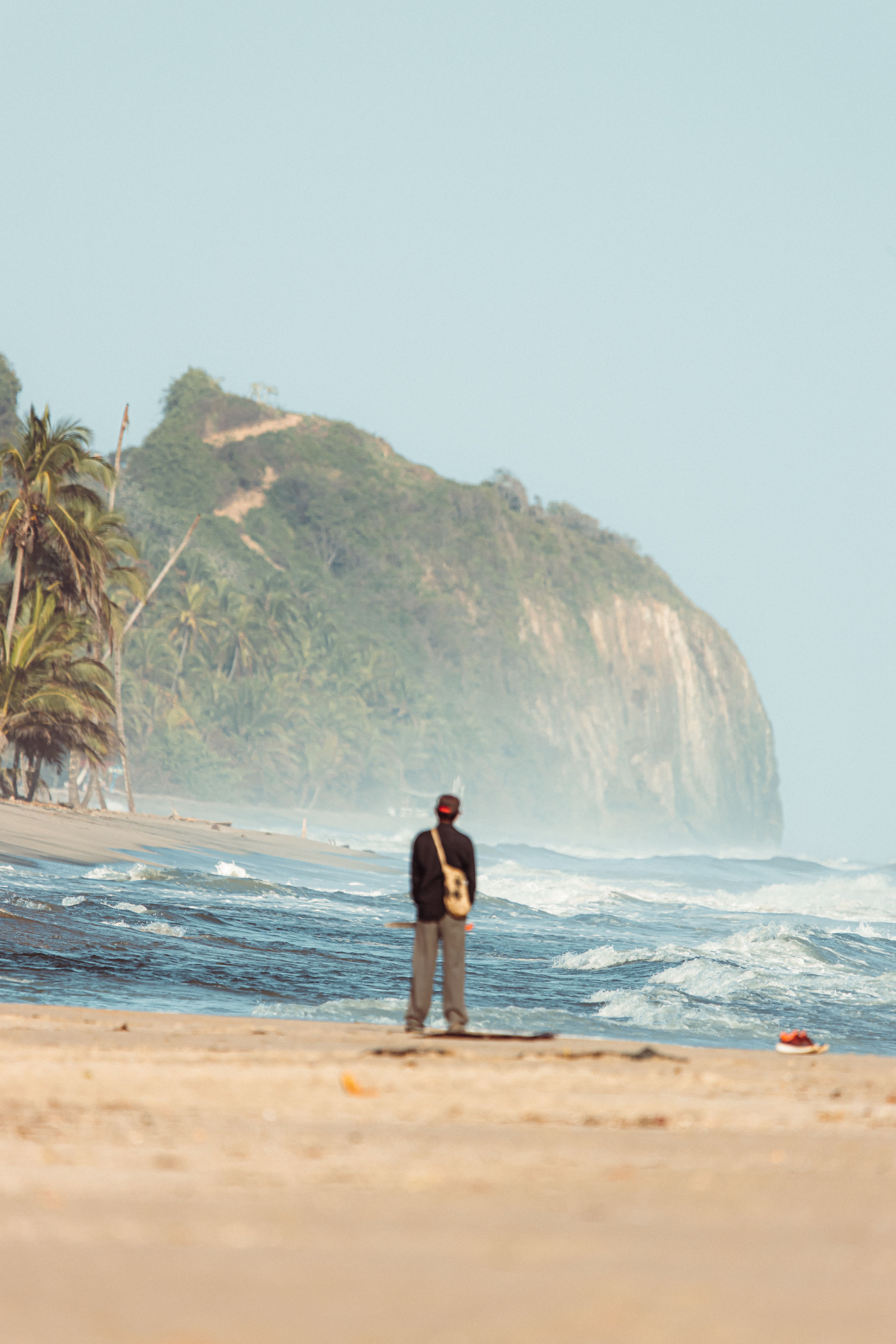 Person Standing on Beach on Sea Shore · Free Stock Photo