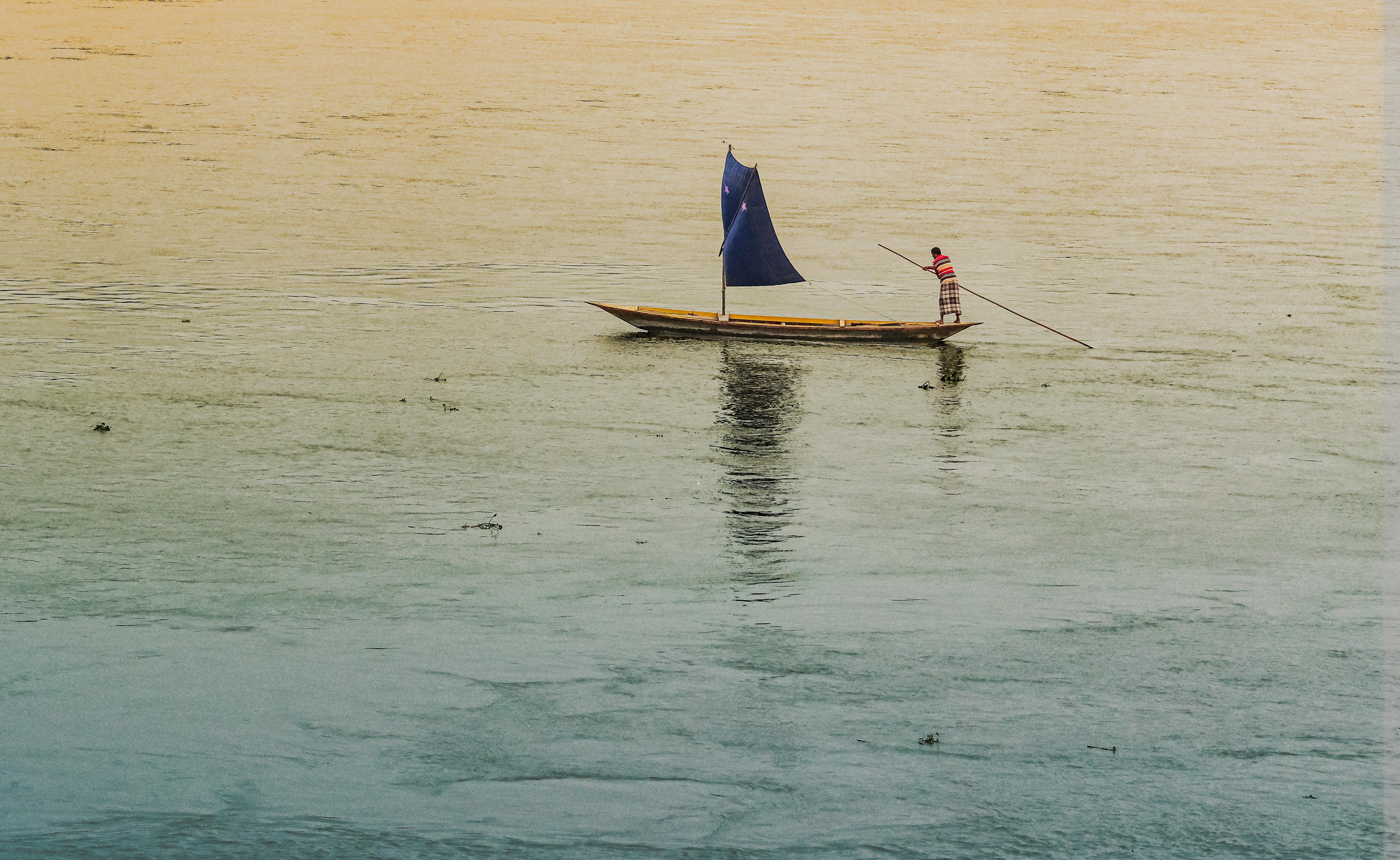 Person Rowing with Rod on Boat with Sail · Free Stock Photo