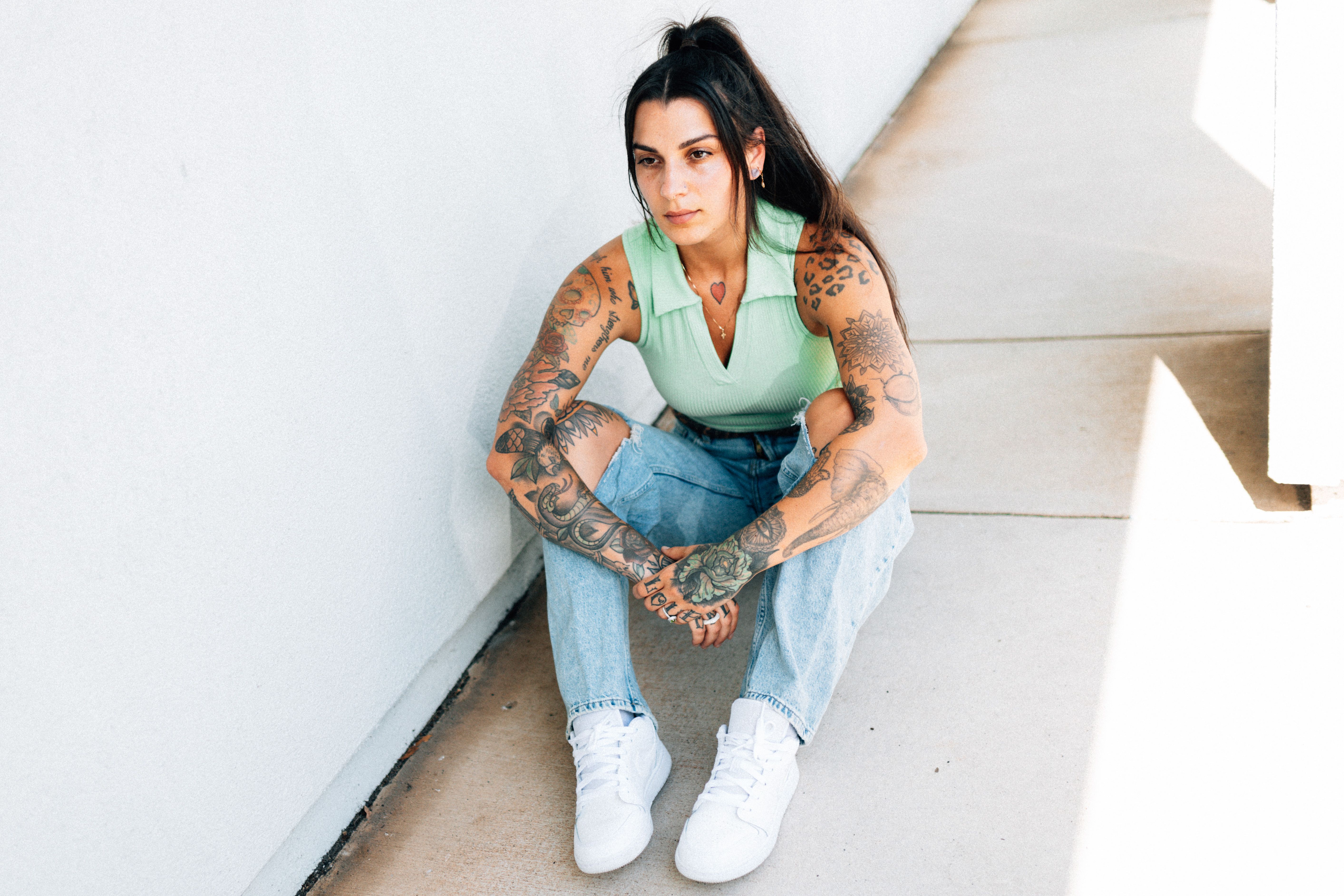 Woman with Tattoos Sitting on Pavement · Free Stock Photo