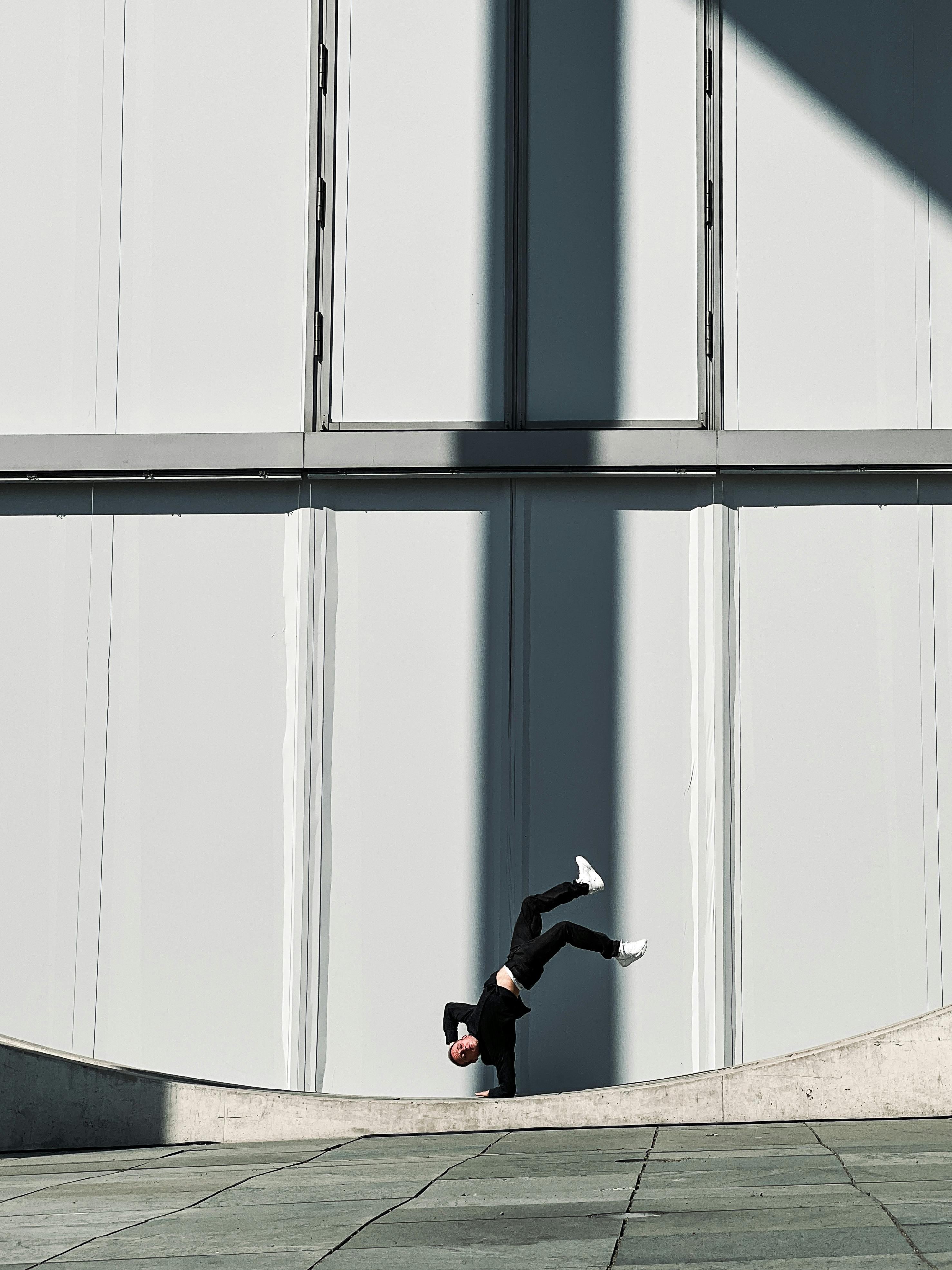 A Man Standing on One Hand in front of a Modern Building · Free Stock Photo