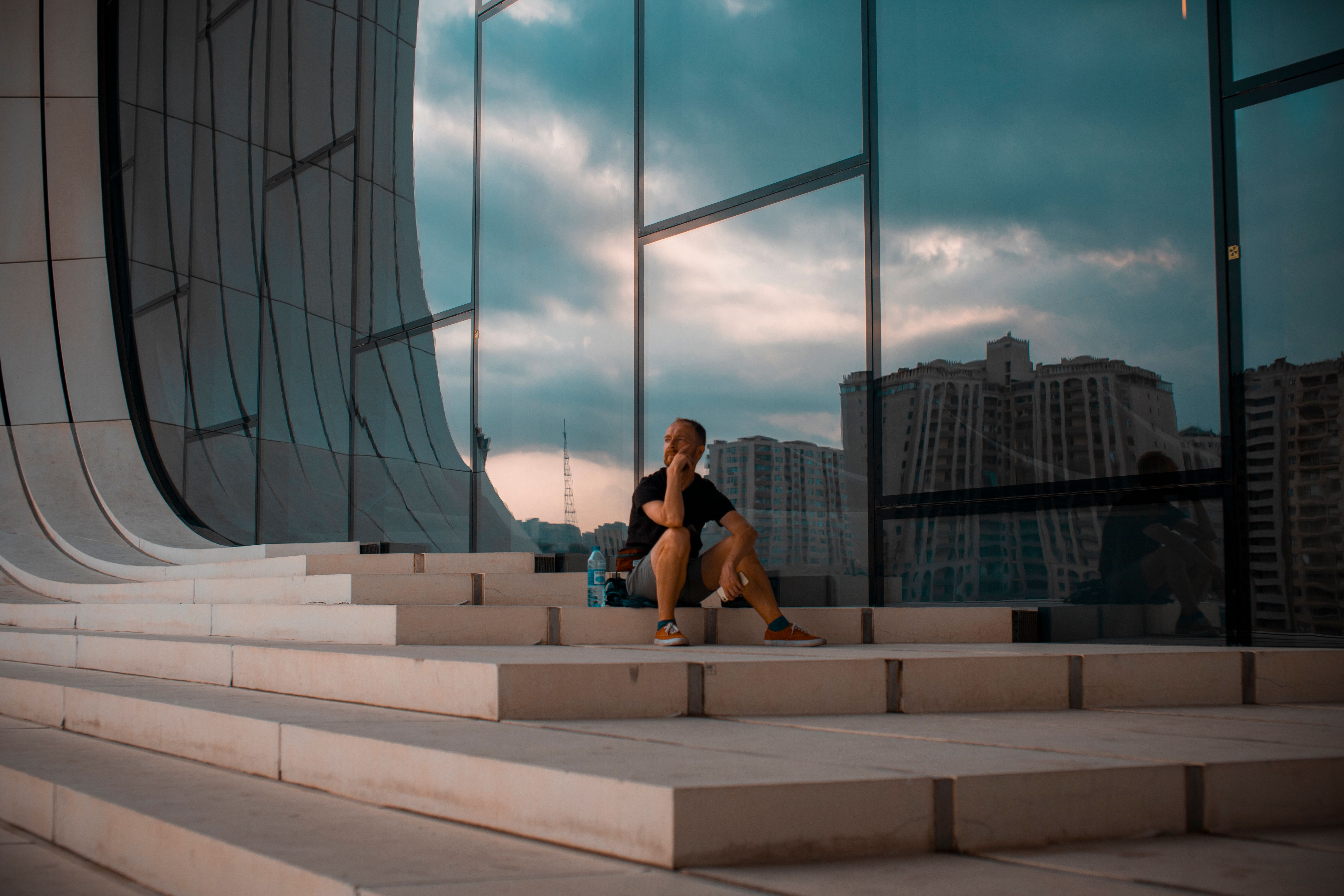 A Man Sitting in Front of a Building · Free Stock Photo