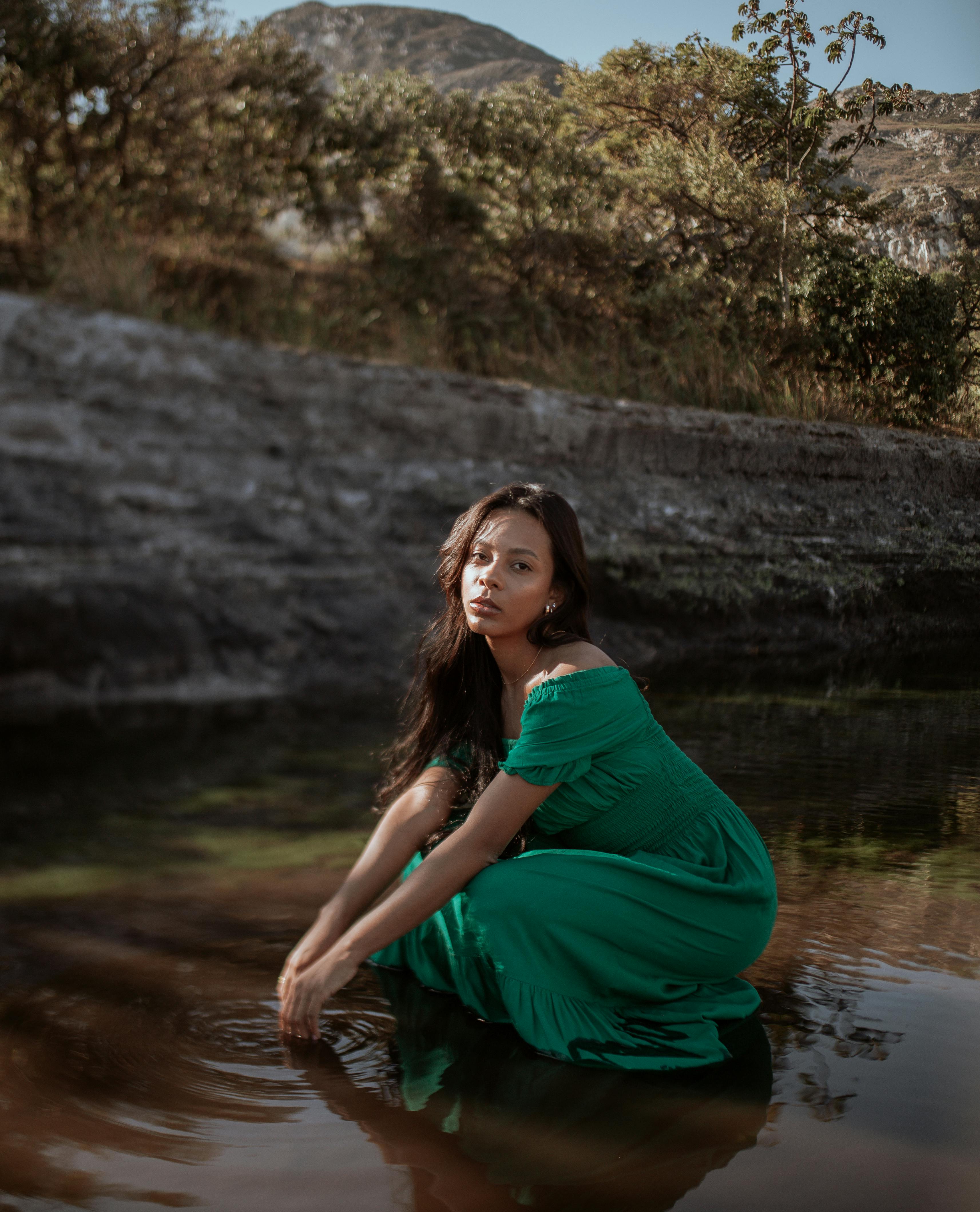 Woman in Greed Dress Crouching in Water · Free Stock Photo