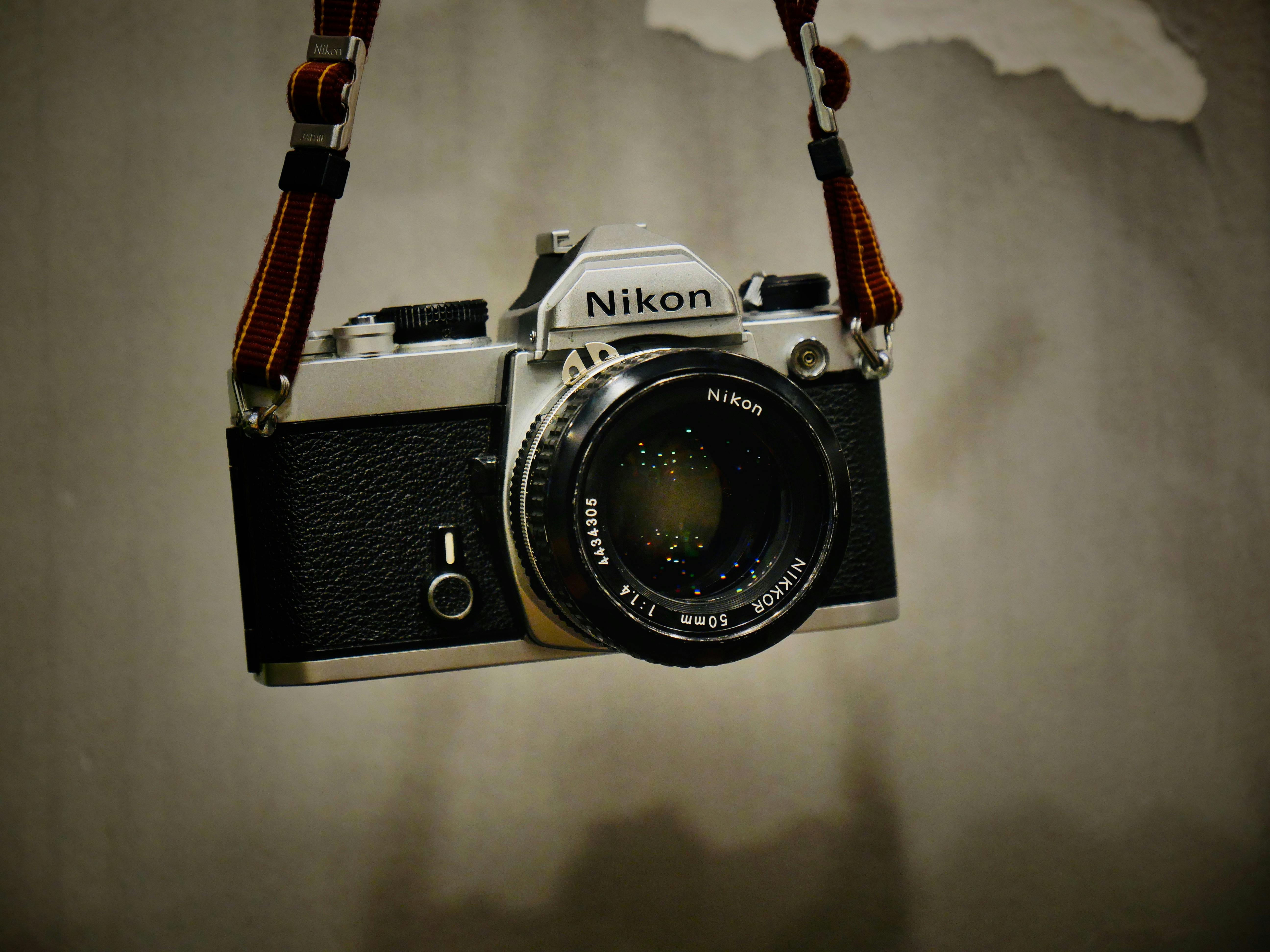 Nikon Camera Hanging on Gray Background · Free Stock Photo