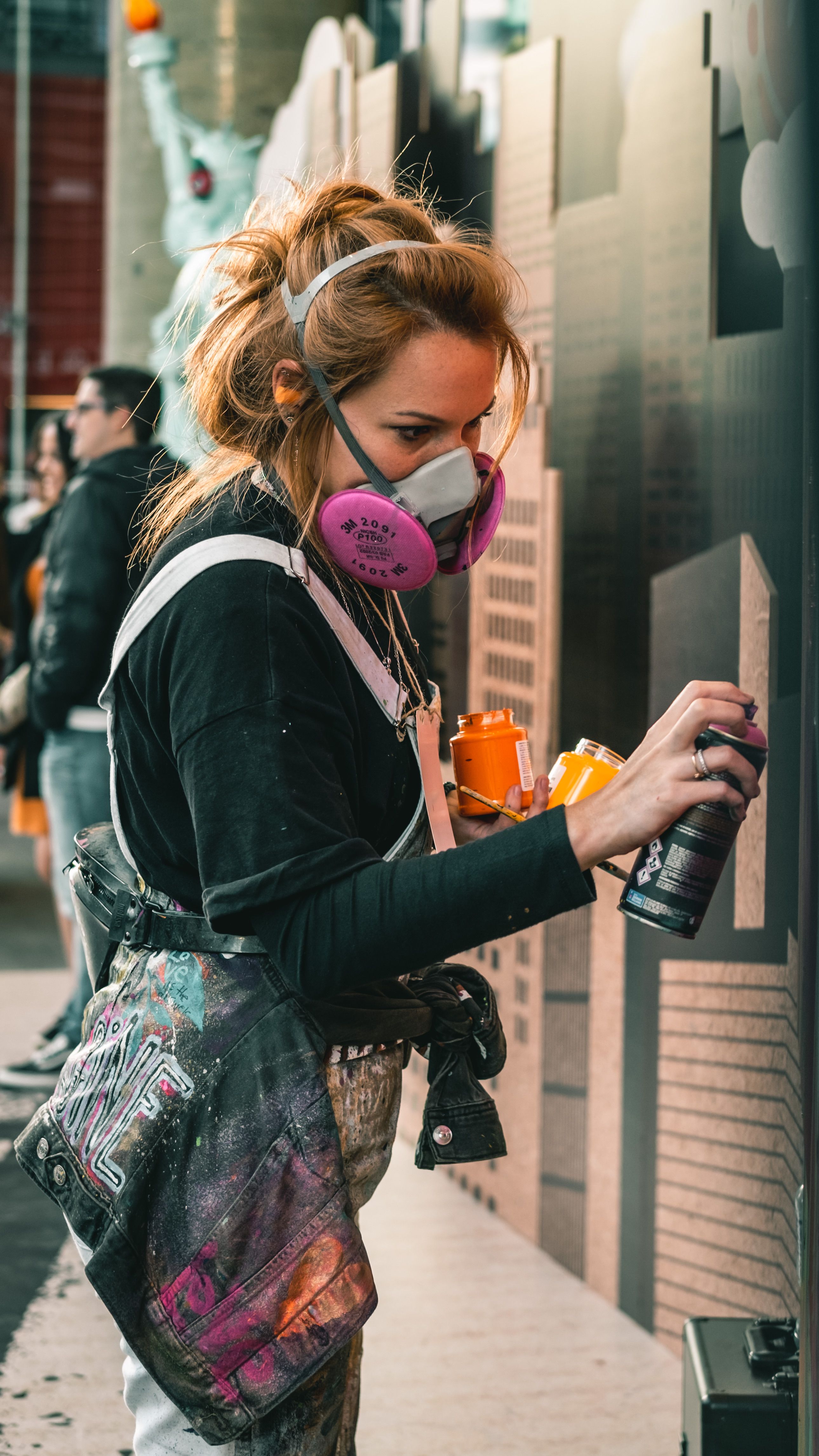 Woman in a Mask Painting with a Spray Paint on a Street · Free Stock Photo