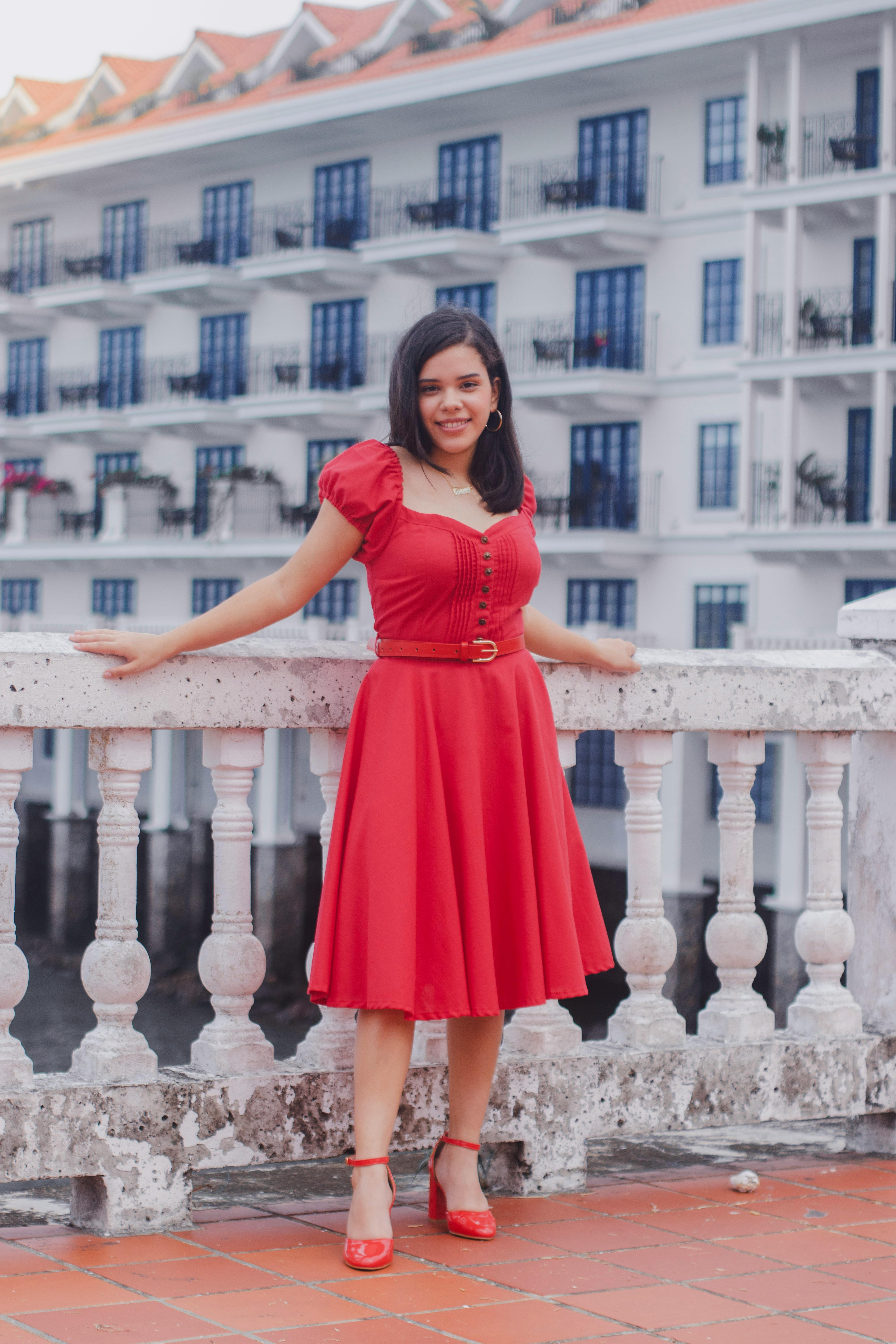 Smiling Woman in Red Dress and Heels Standing on Bridge · Free Stock Photo