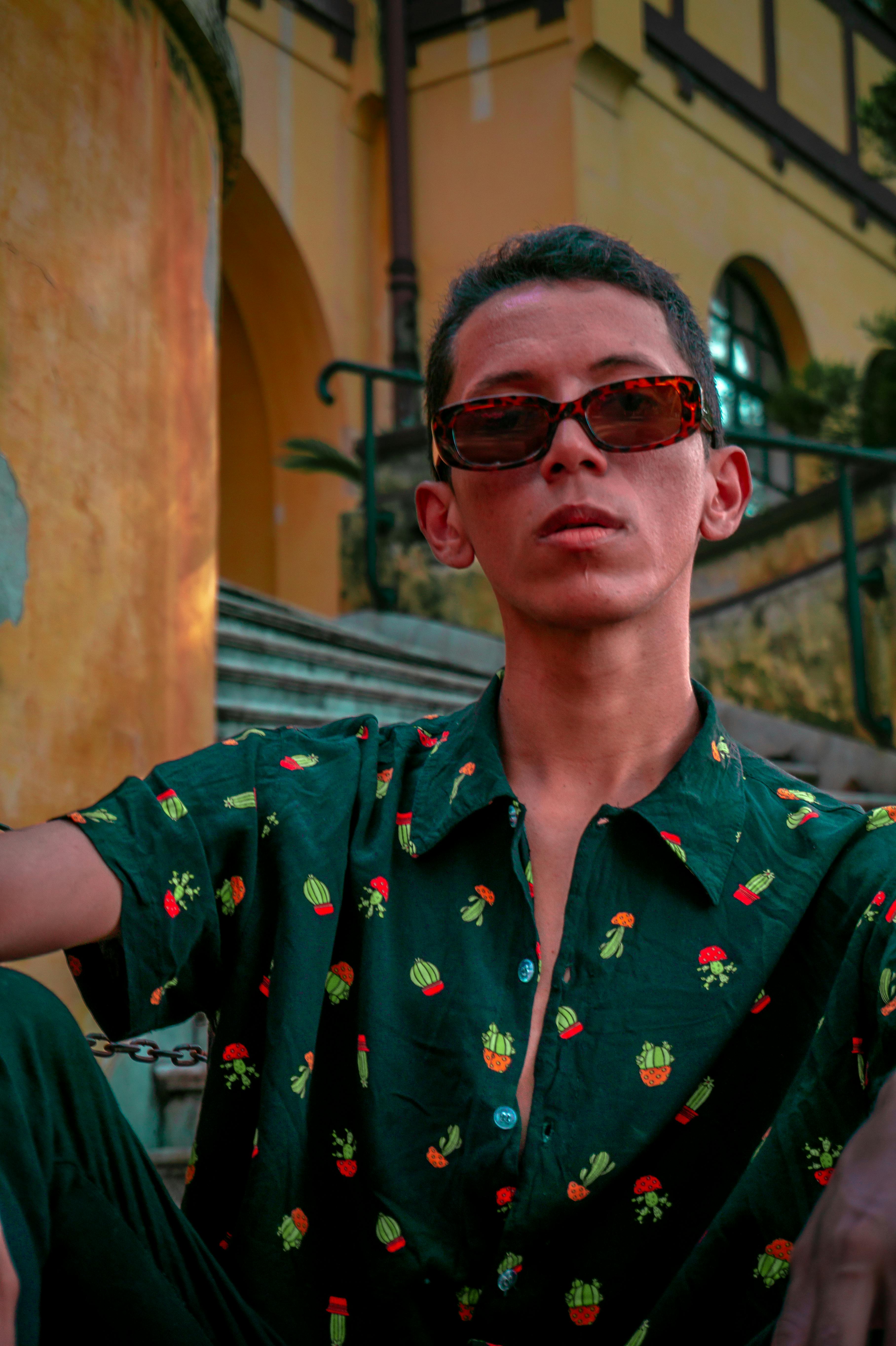 A man in sunglasses and a green shirt sitting on steps · Free Stock Photo