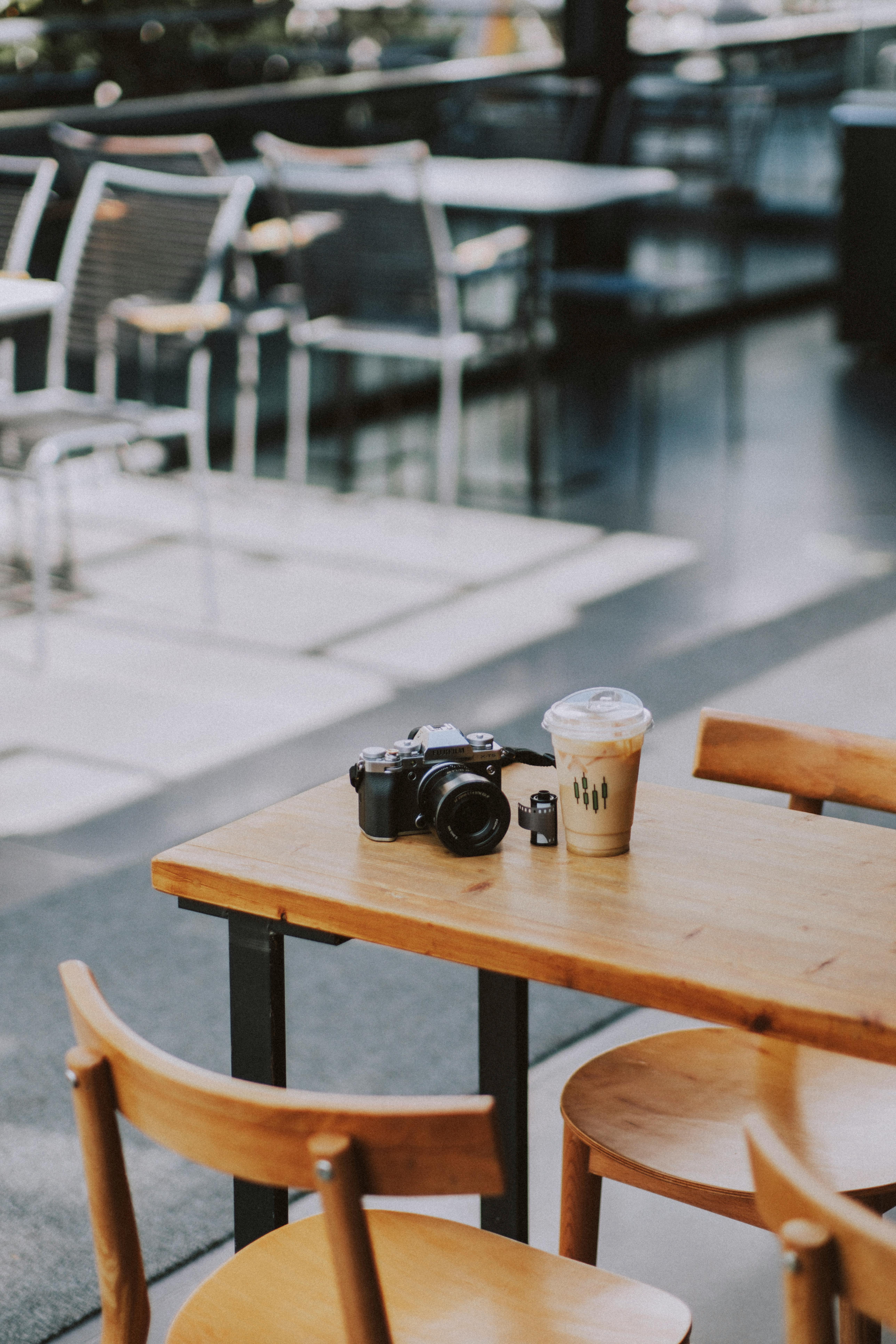 Camera and a Disposable Coffee Cup on a Table · Free Stock Photo