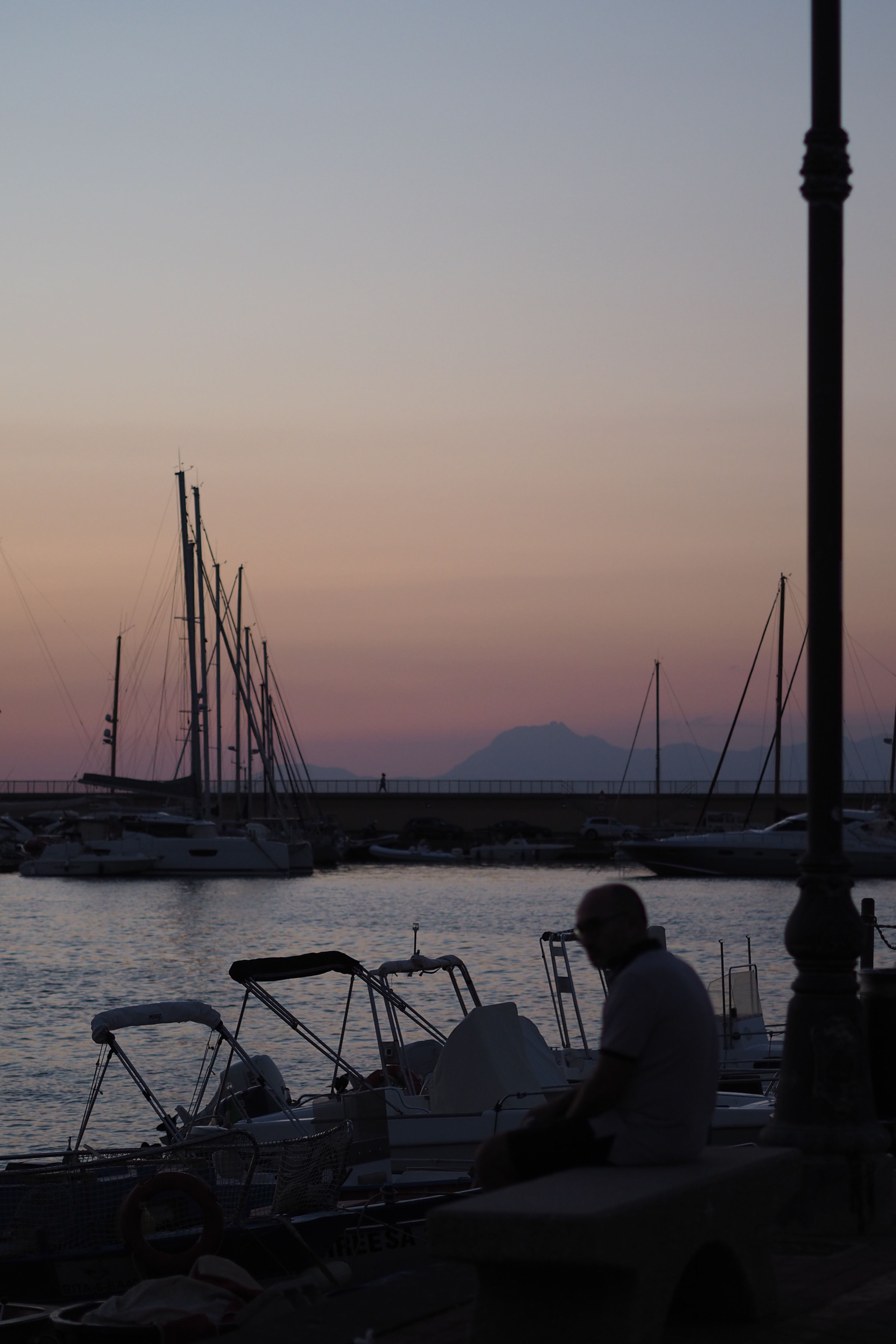 Man Sitting in a Marina at Dusk · Free Stock Photo