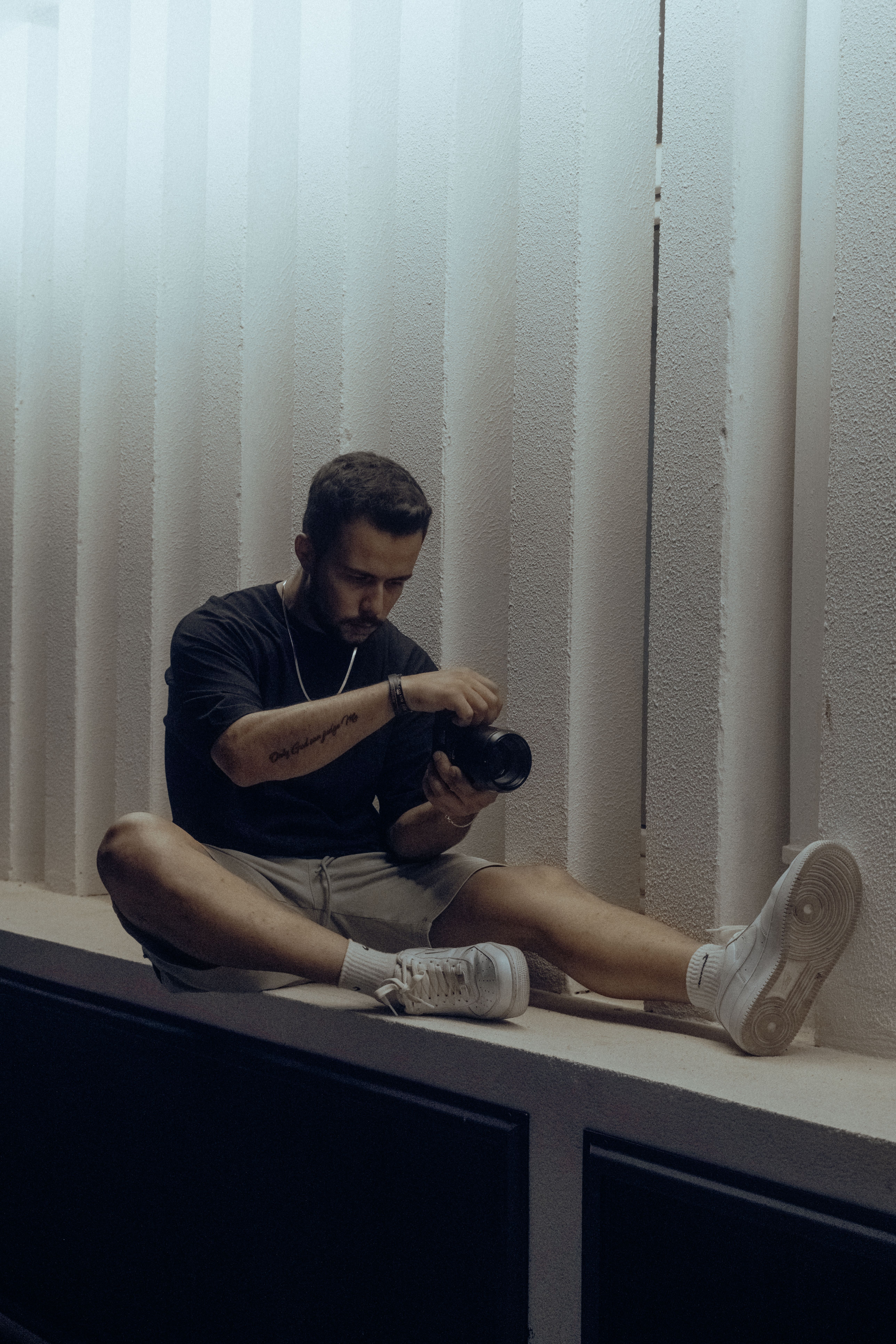 Photographer Sitting with Camera on Wall · Free Stock Photo
