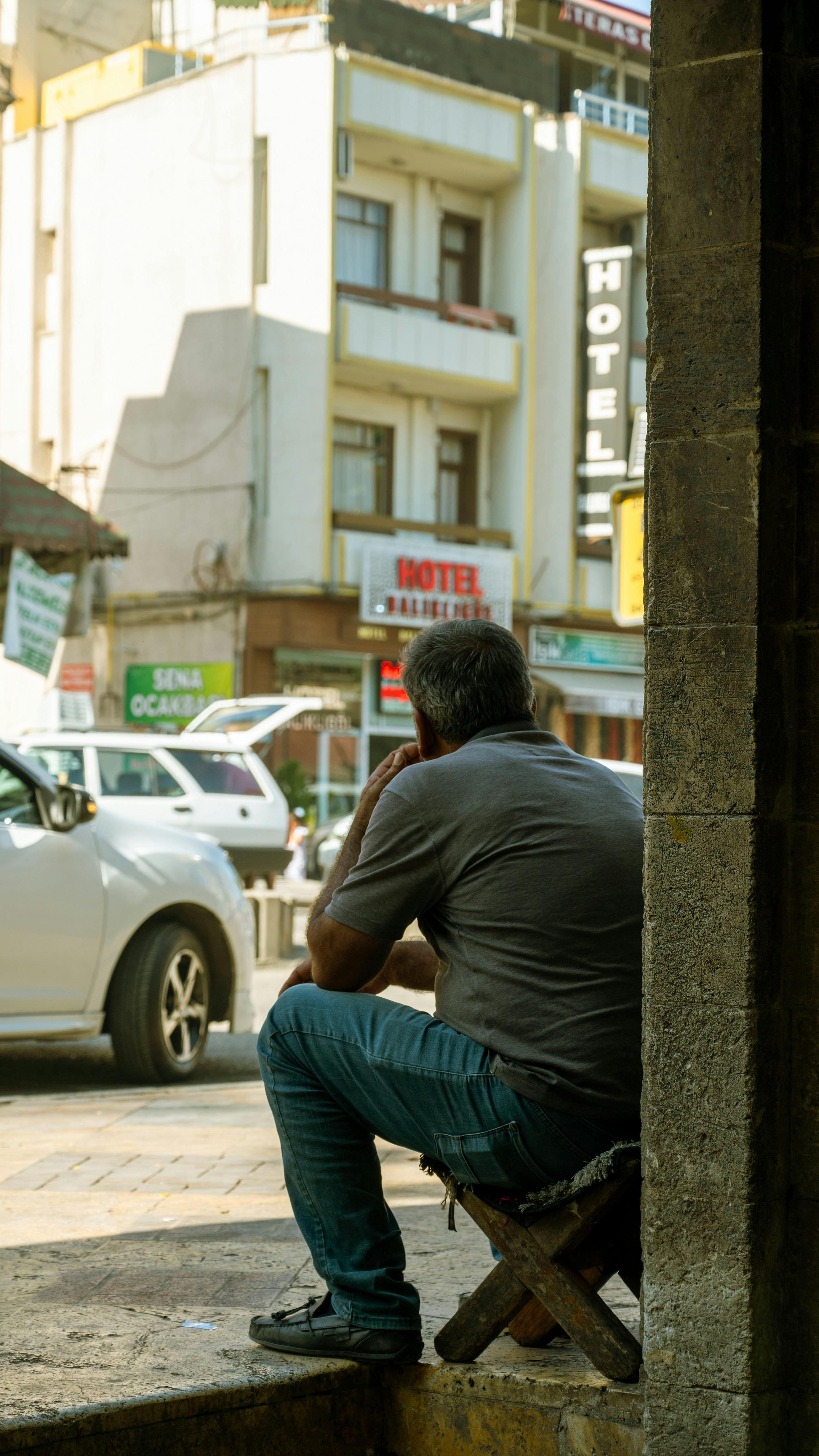 Man Sitting on Stool at Sidewalk · Free Stock Photo