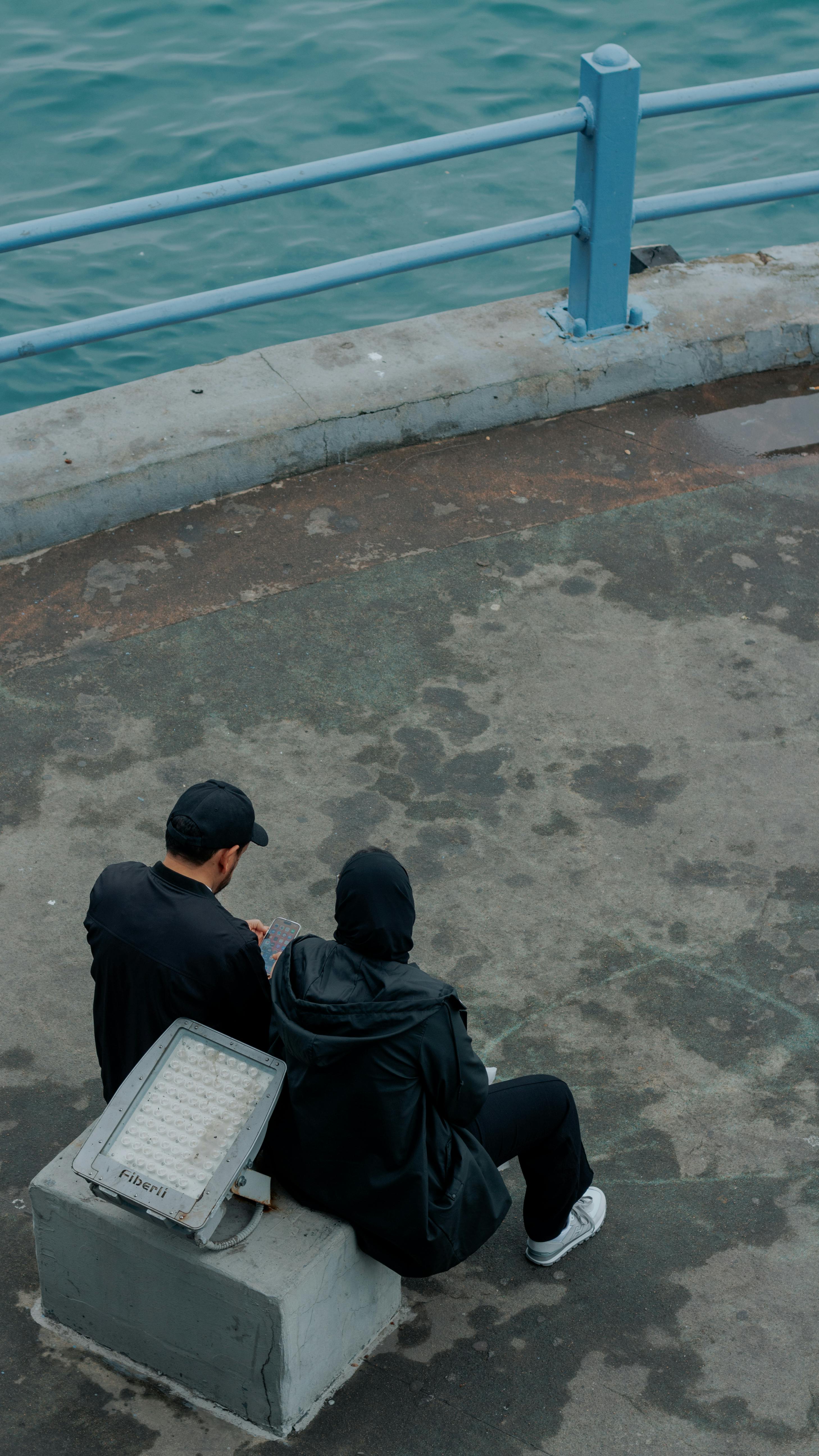 Two People Sitting Together by a Coastal Spotlight · Free Stock Photo
