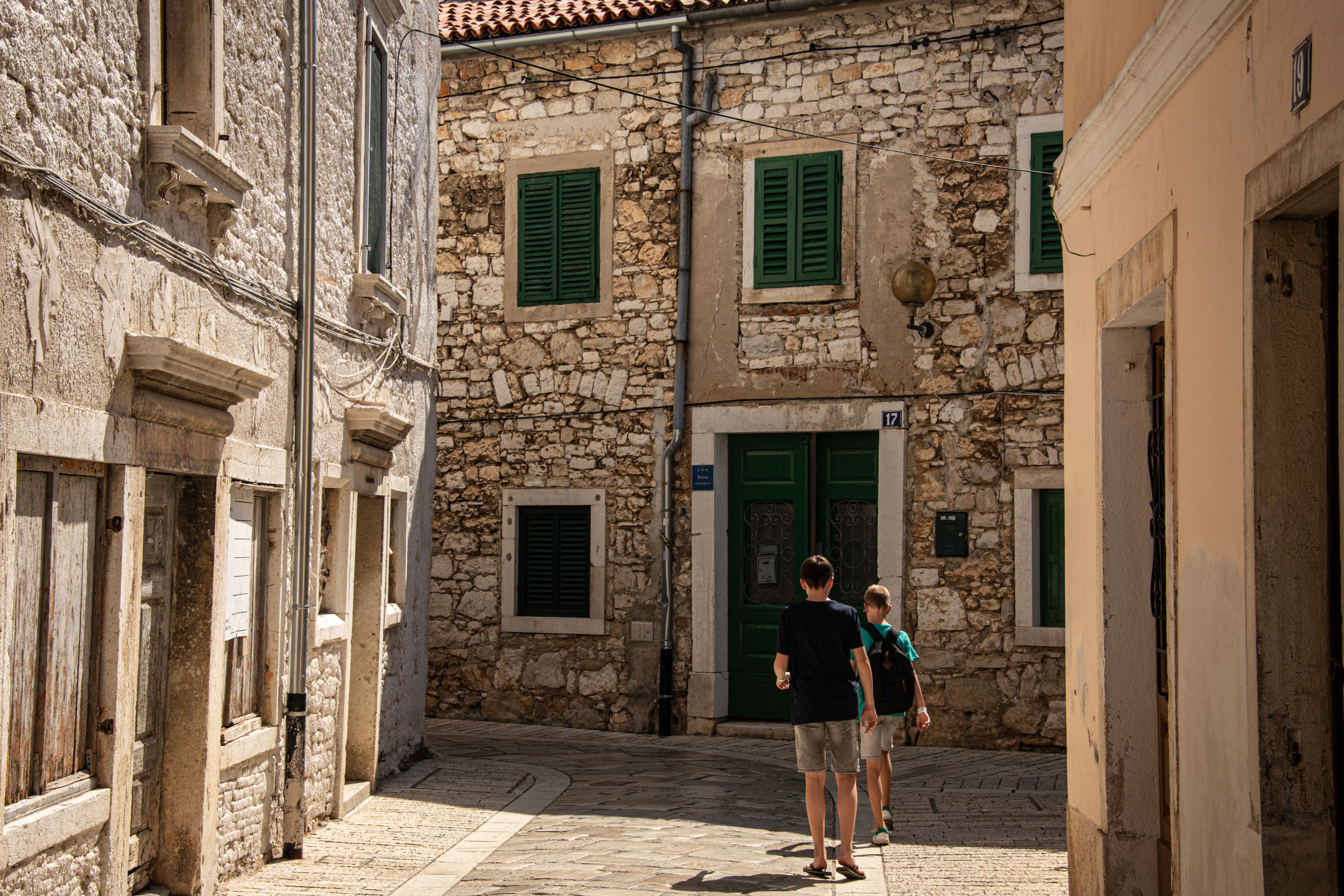 Two Boys Walking in a Historic Alley · Free Stock Photo