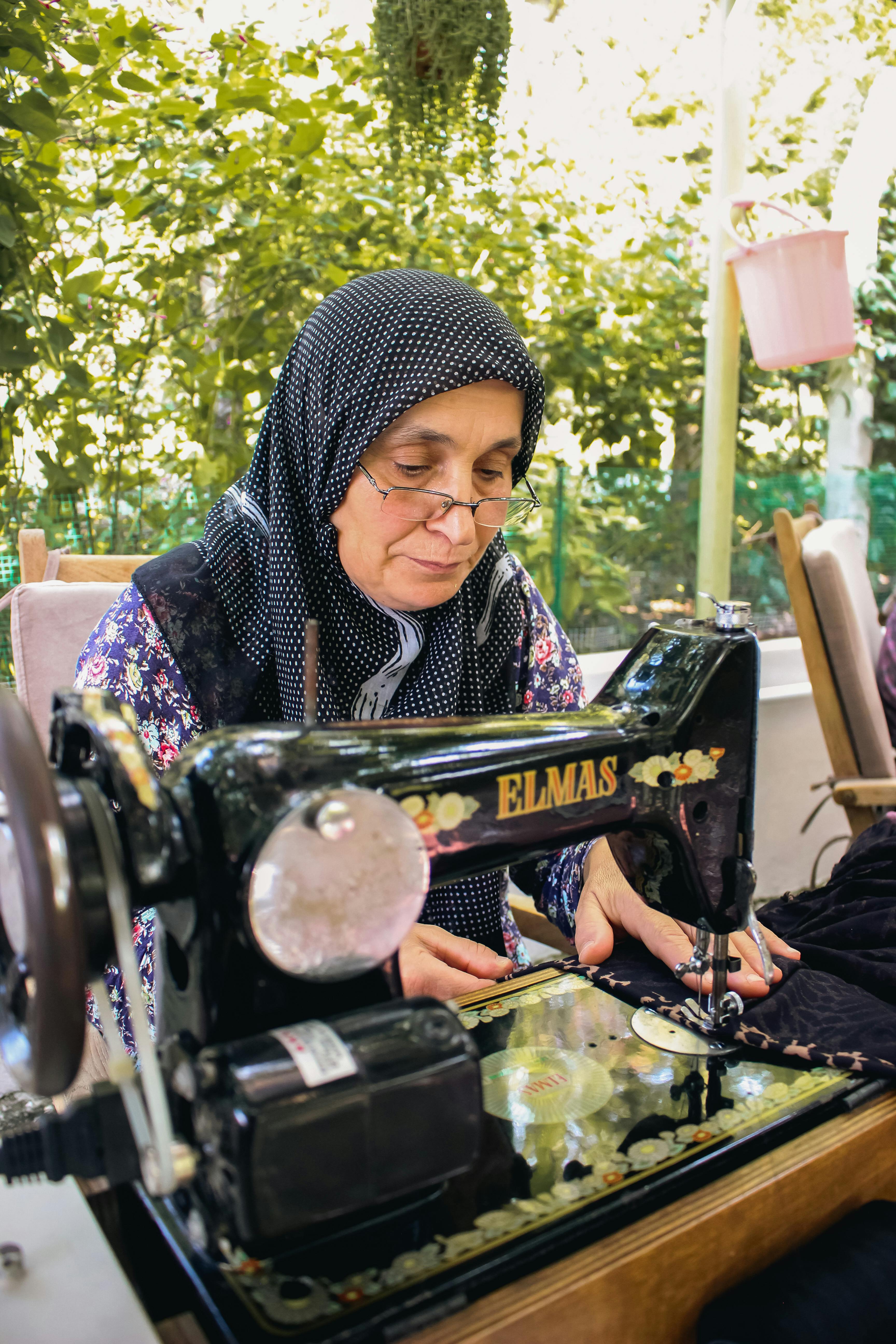Woman in Hijab Sitting and Working on Sewing Machine · Free Stock Photo