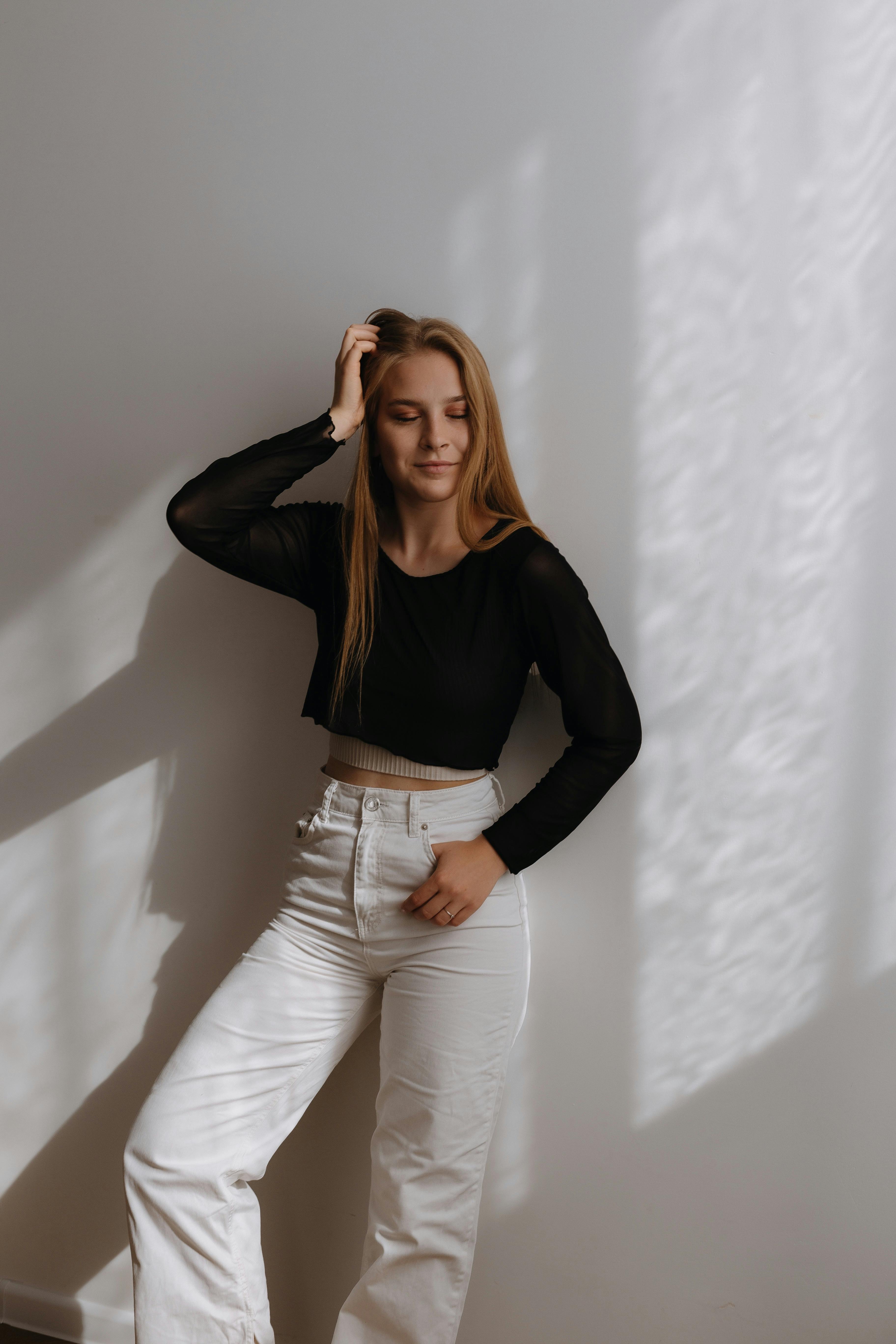 Shadow Cast on Woman Standing under White Wall · Free Stock Photo