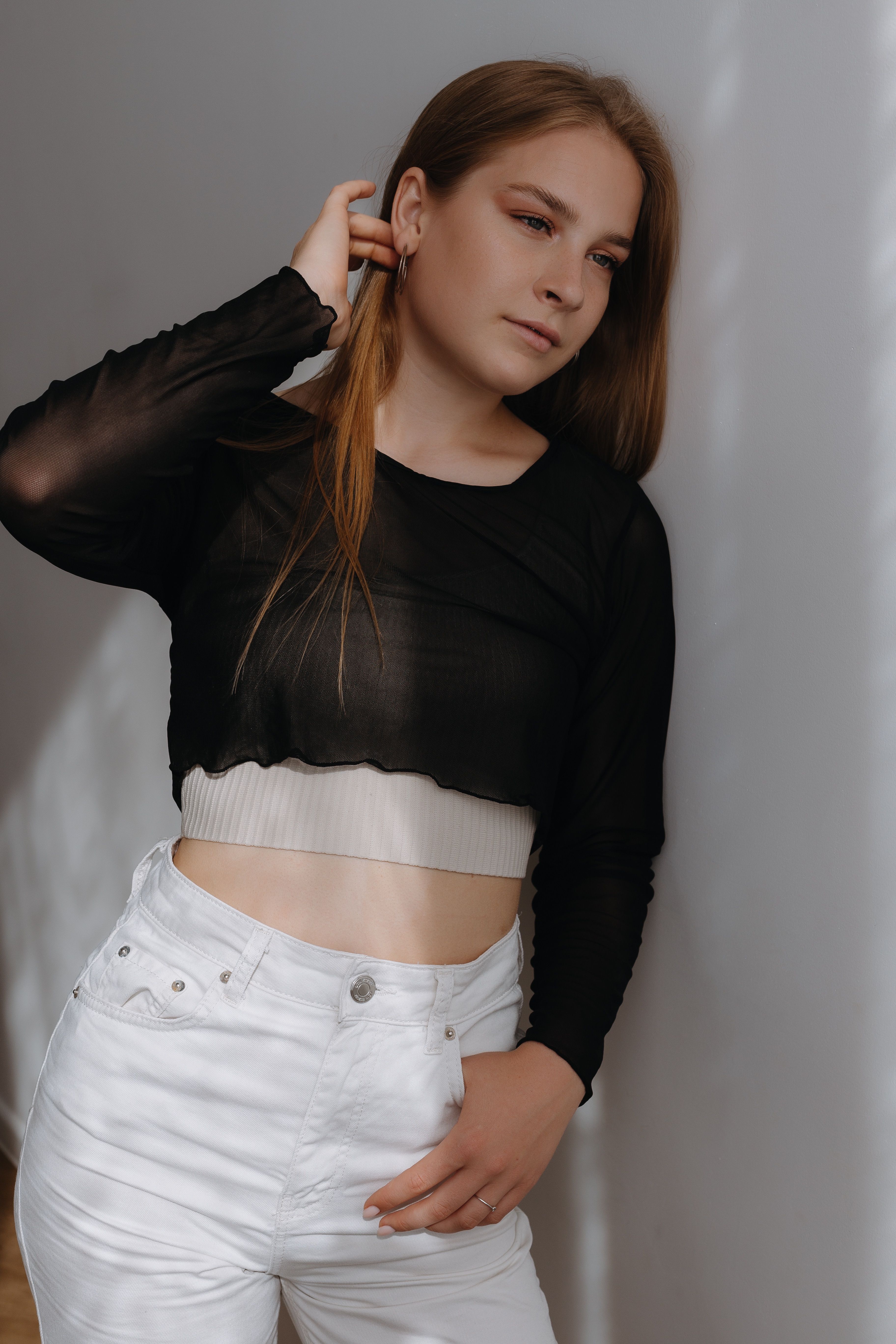 Young Woman In White Jeans And Black See Through Crop Top Fixing Her