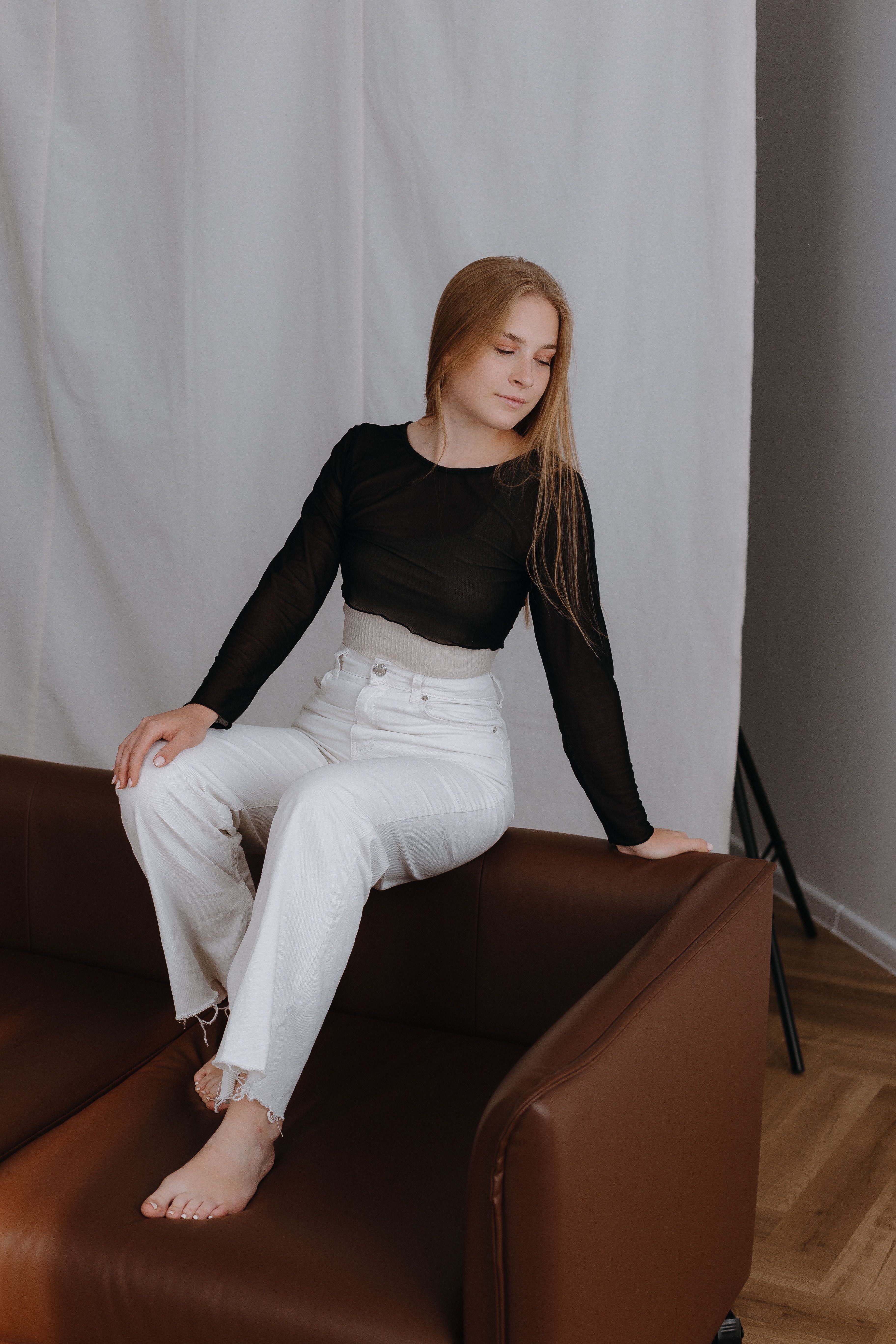 Photo of a Girl Wearing White Trousers Sitting on a Brown Sofa · Free ...
