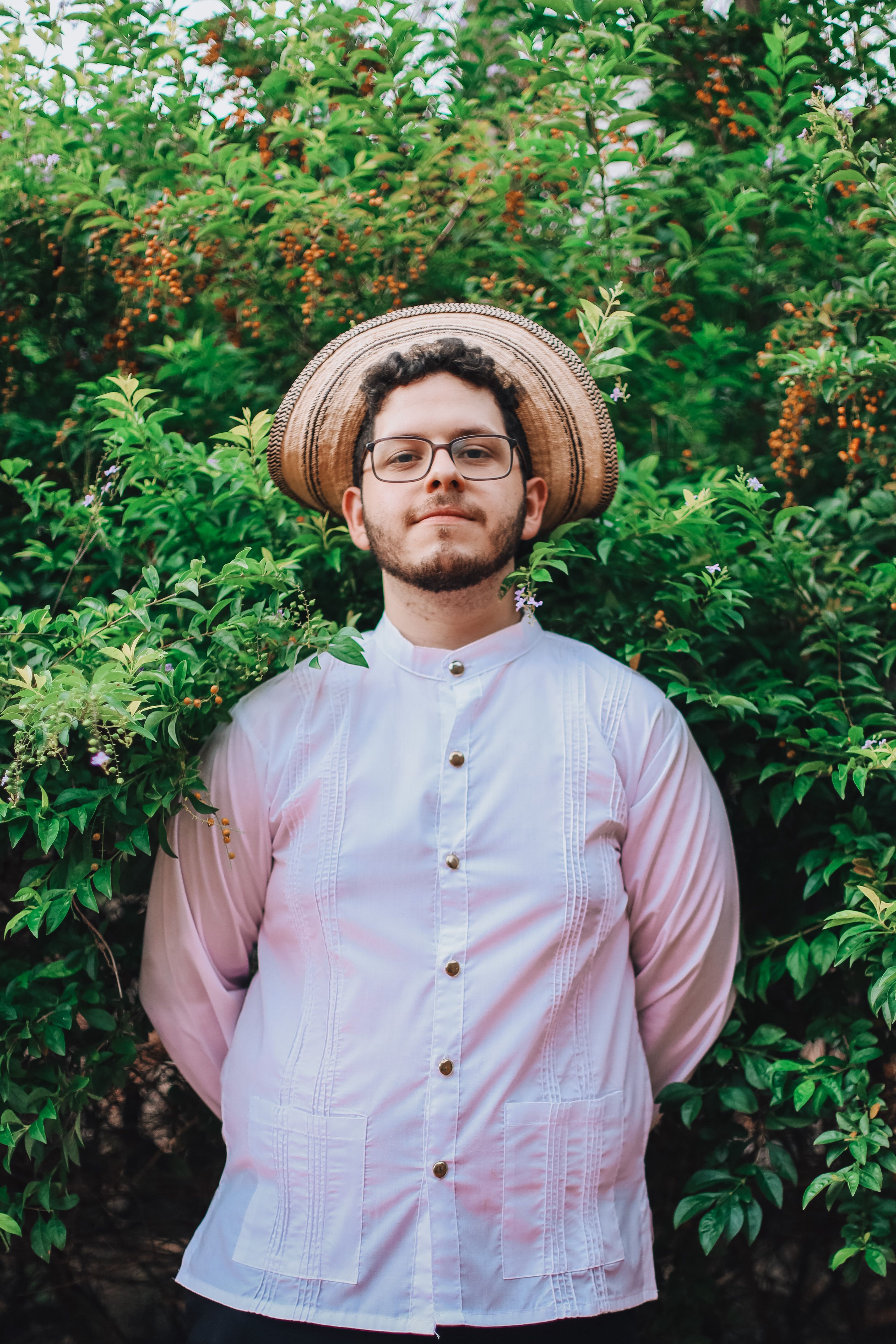 A Man in a Shirt and Hat Standing on the Background of a Shrub · Free ...