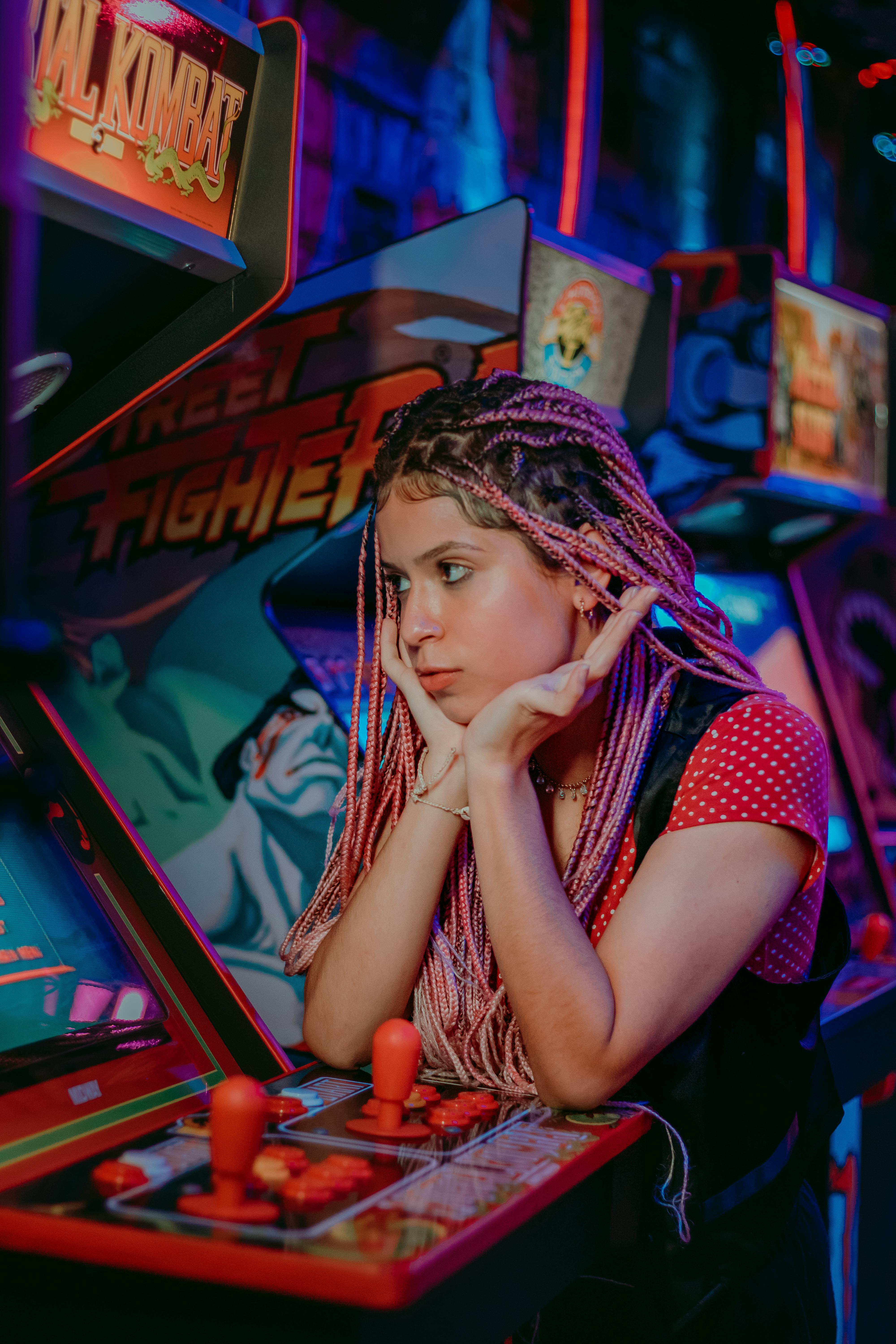 Young Woman Standing beside a Machine in an Arcade · Free Stock Photo