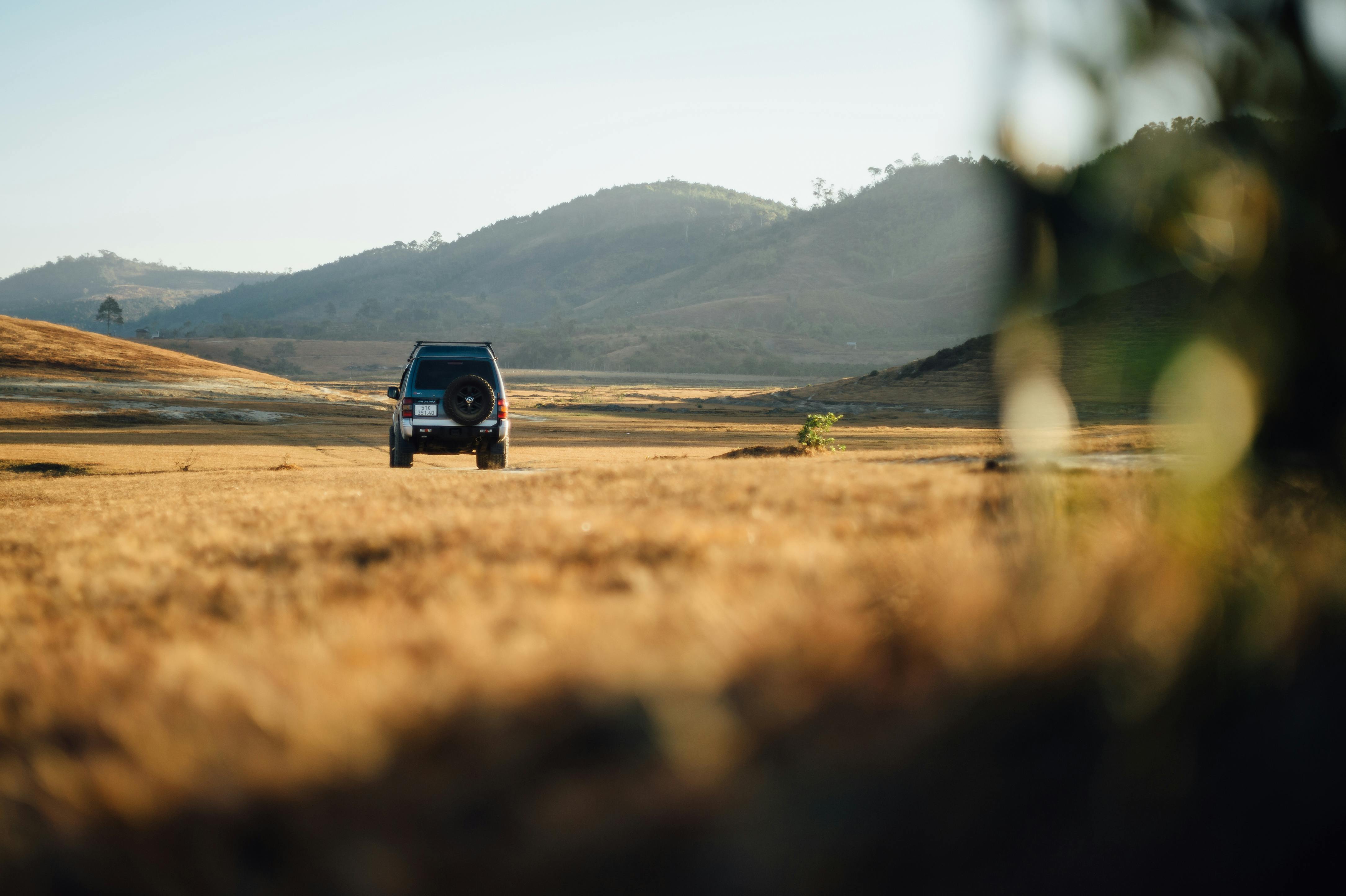 A car driving through a field in the middle of the day · Free Stock Photo