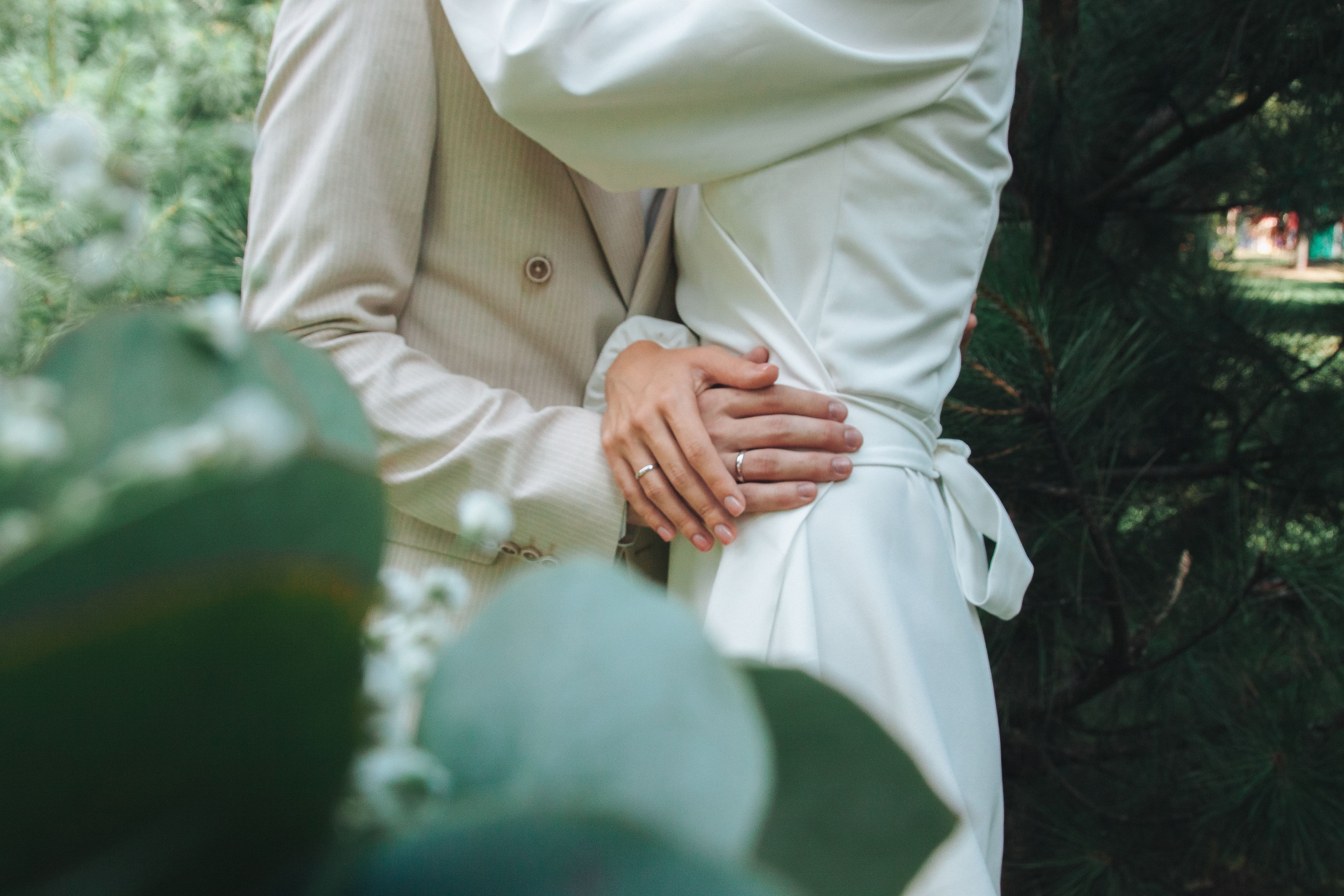 Bride in Long White Gown and Groom in Elegant Suit Posing by Window ...