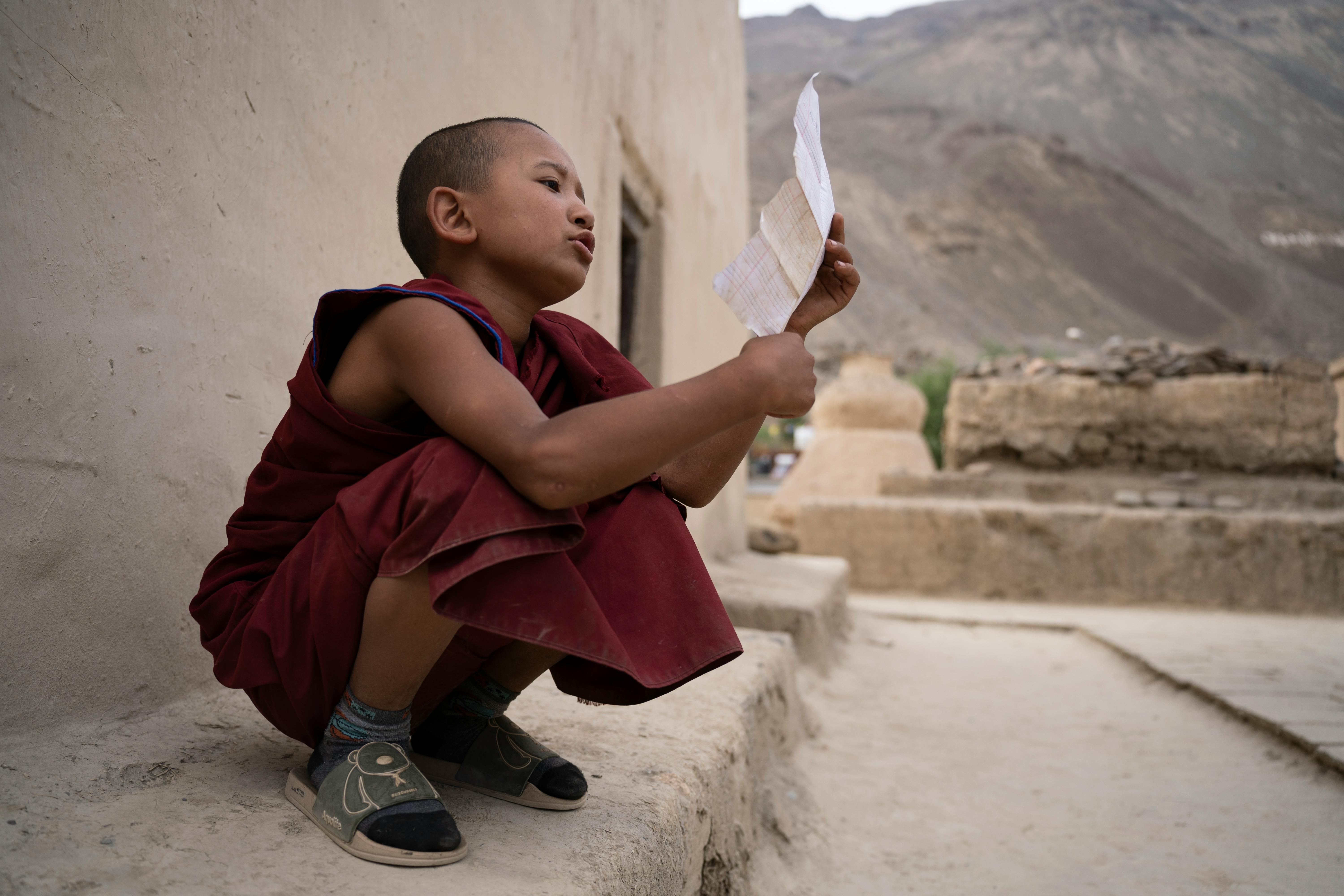 A Young Monk Reading a Note on a Piece of Paper · Free Stock Photo