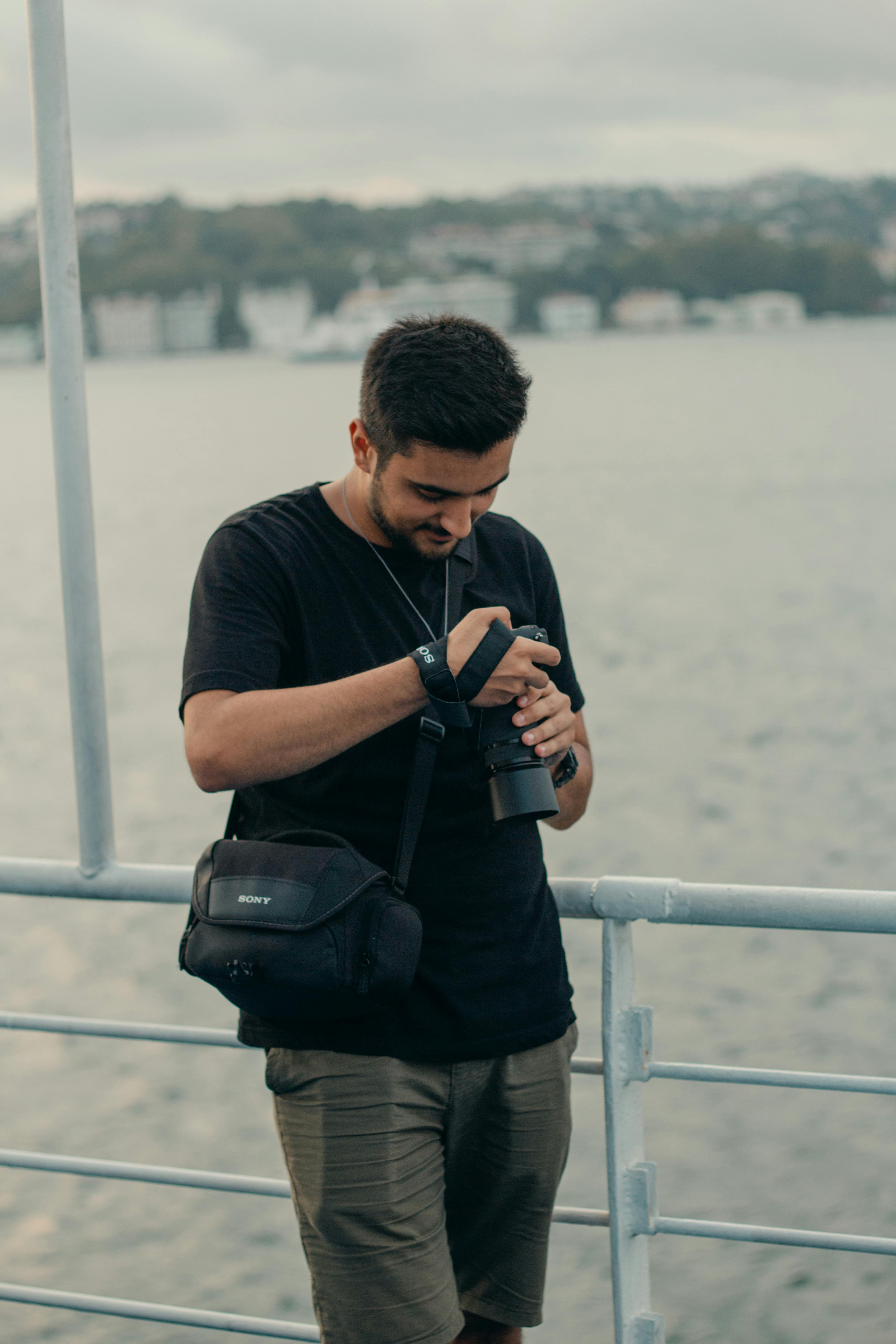 Man Holding a Camera in a Harbor · Free Stock Photo