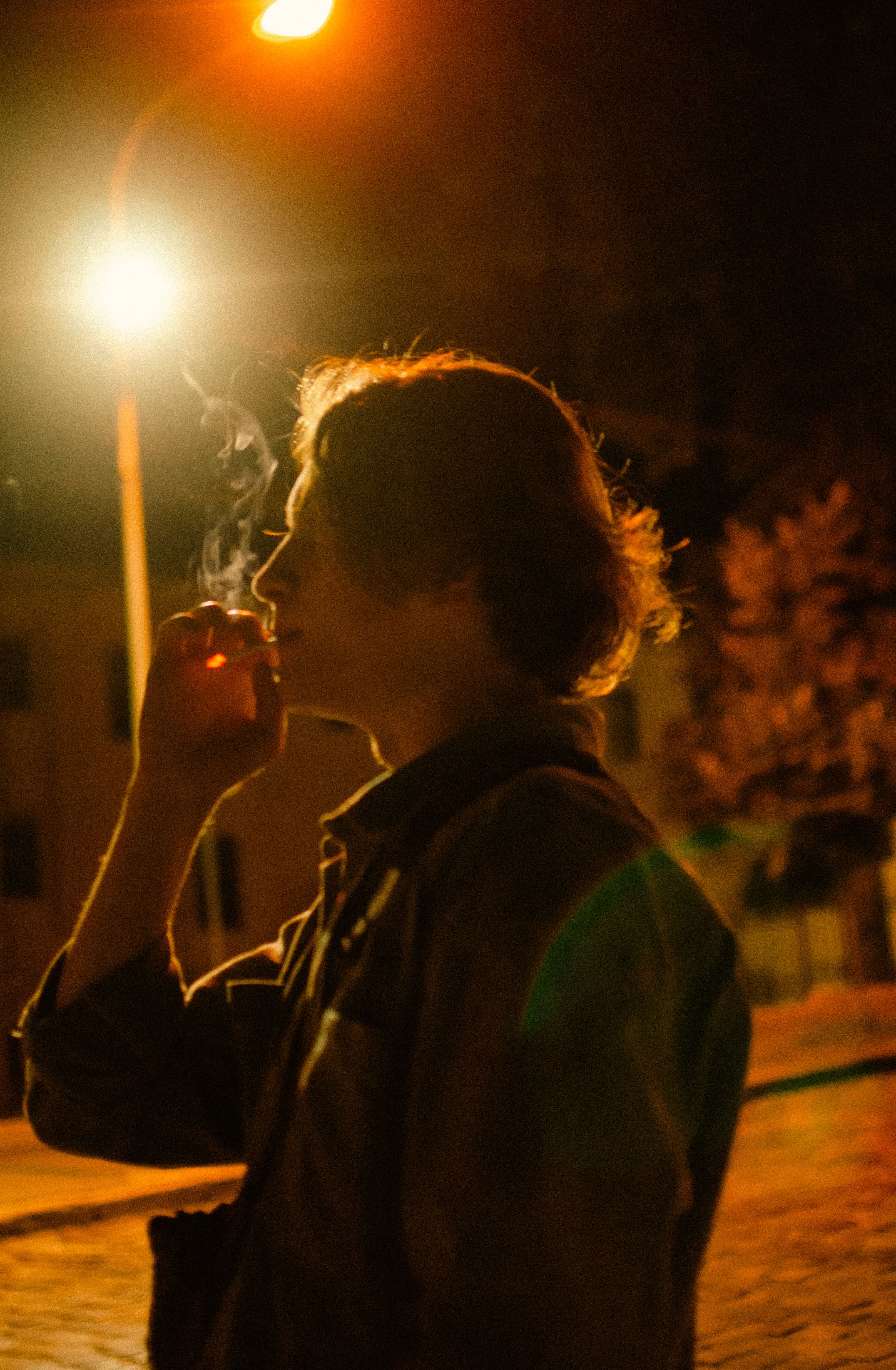 Light over Man Smoking Cigarette on Street at Night · Free Stock Photo