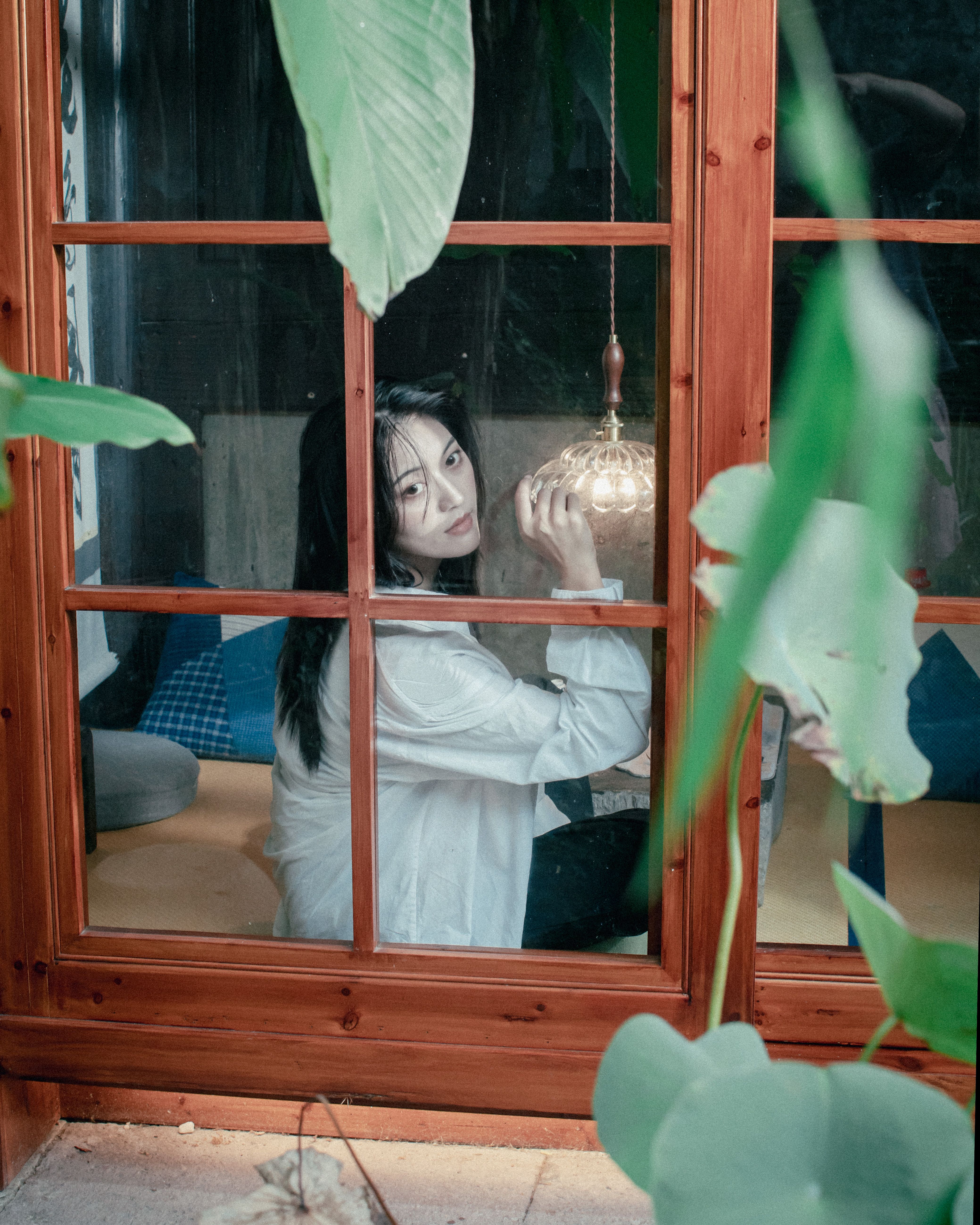 Woman Sitting with Lamp behind Windows · Free Stock Photo