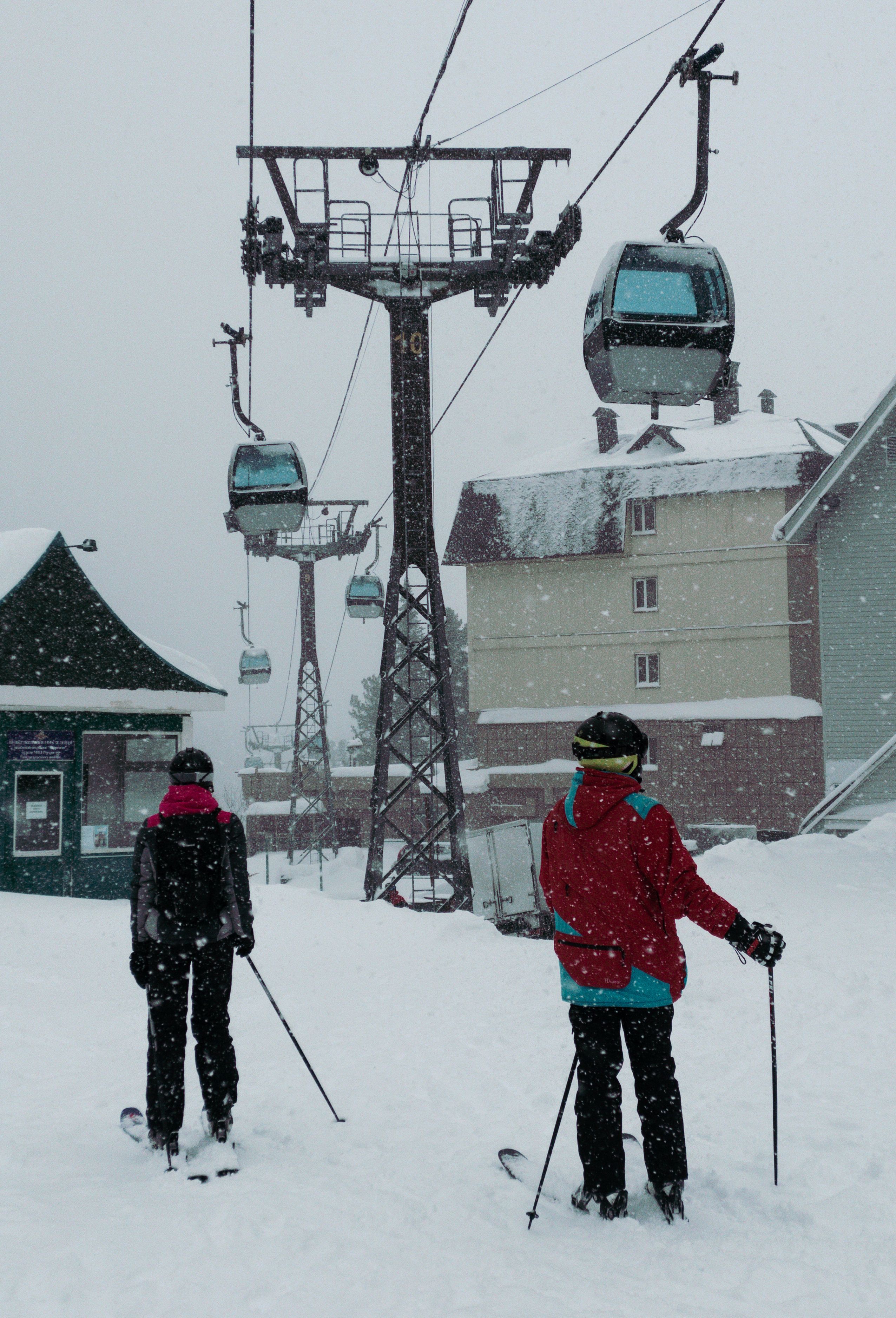 Two people on skis in the snow near a ski lift · Free Stock Photo