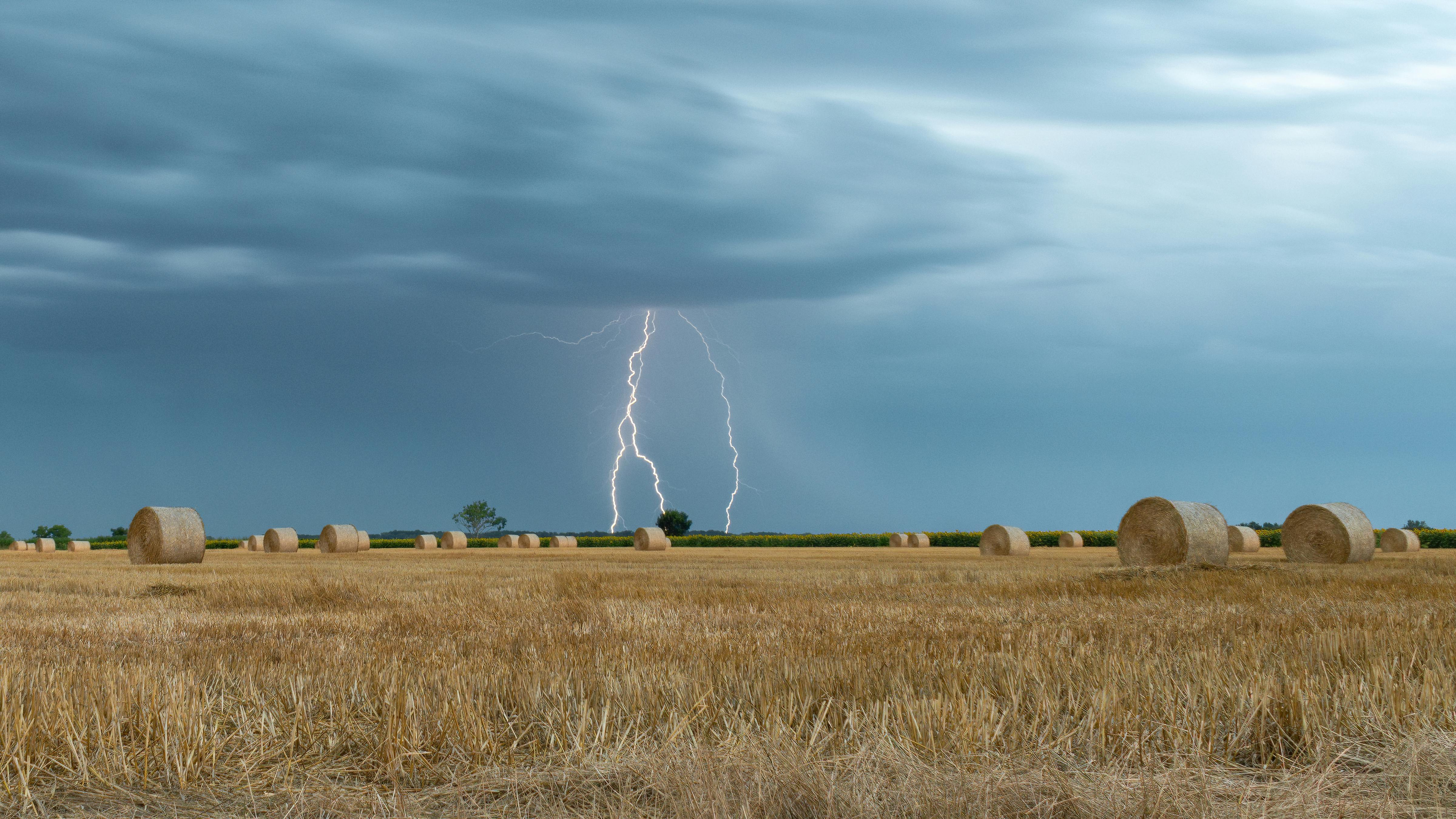 Lighting over Farm Field with Bales of Hay · Free Stock Photo