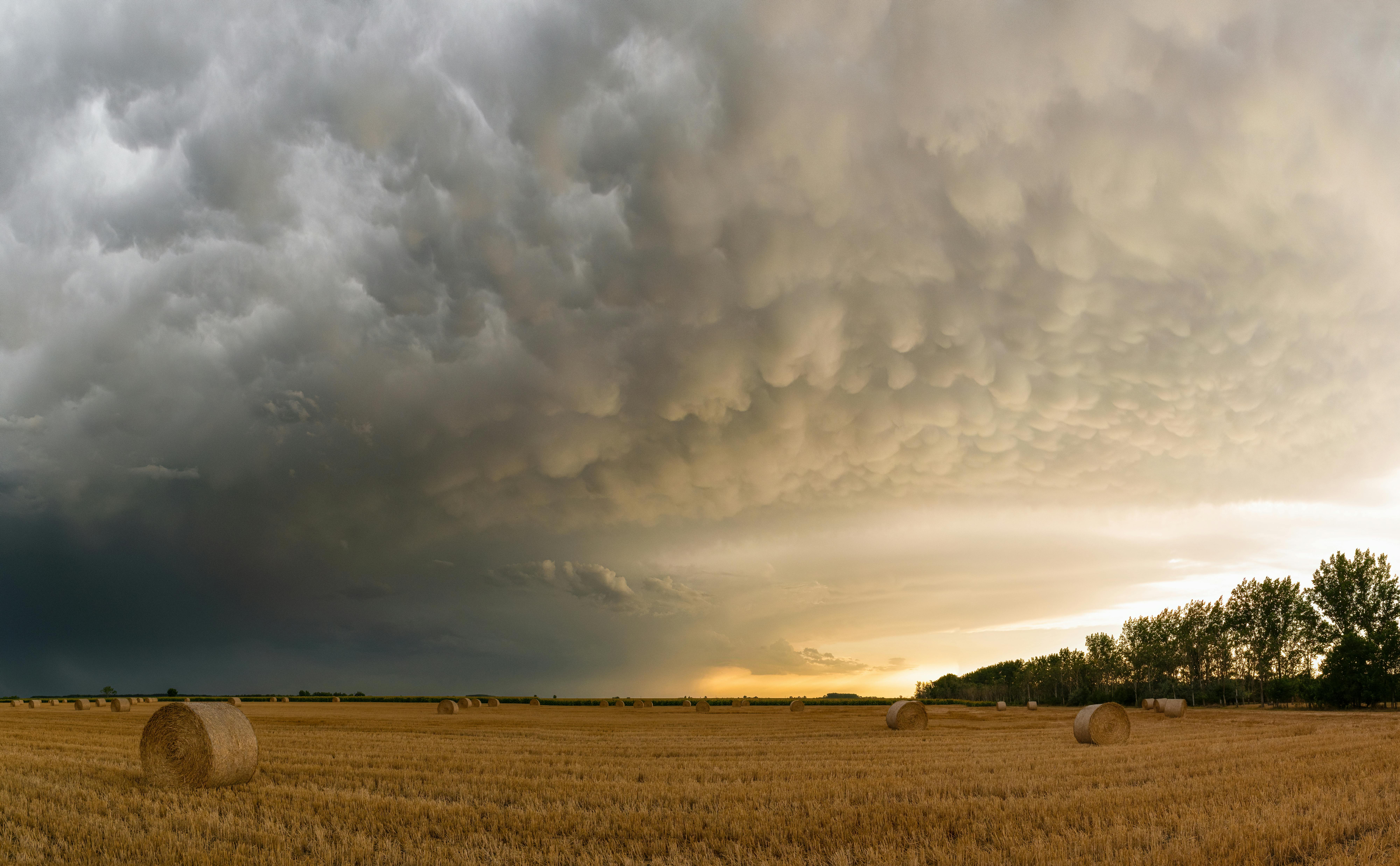 Storm Clouds over Rural Field with Bales of Hay · Free Stock Photo