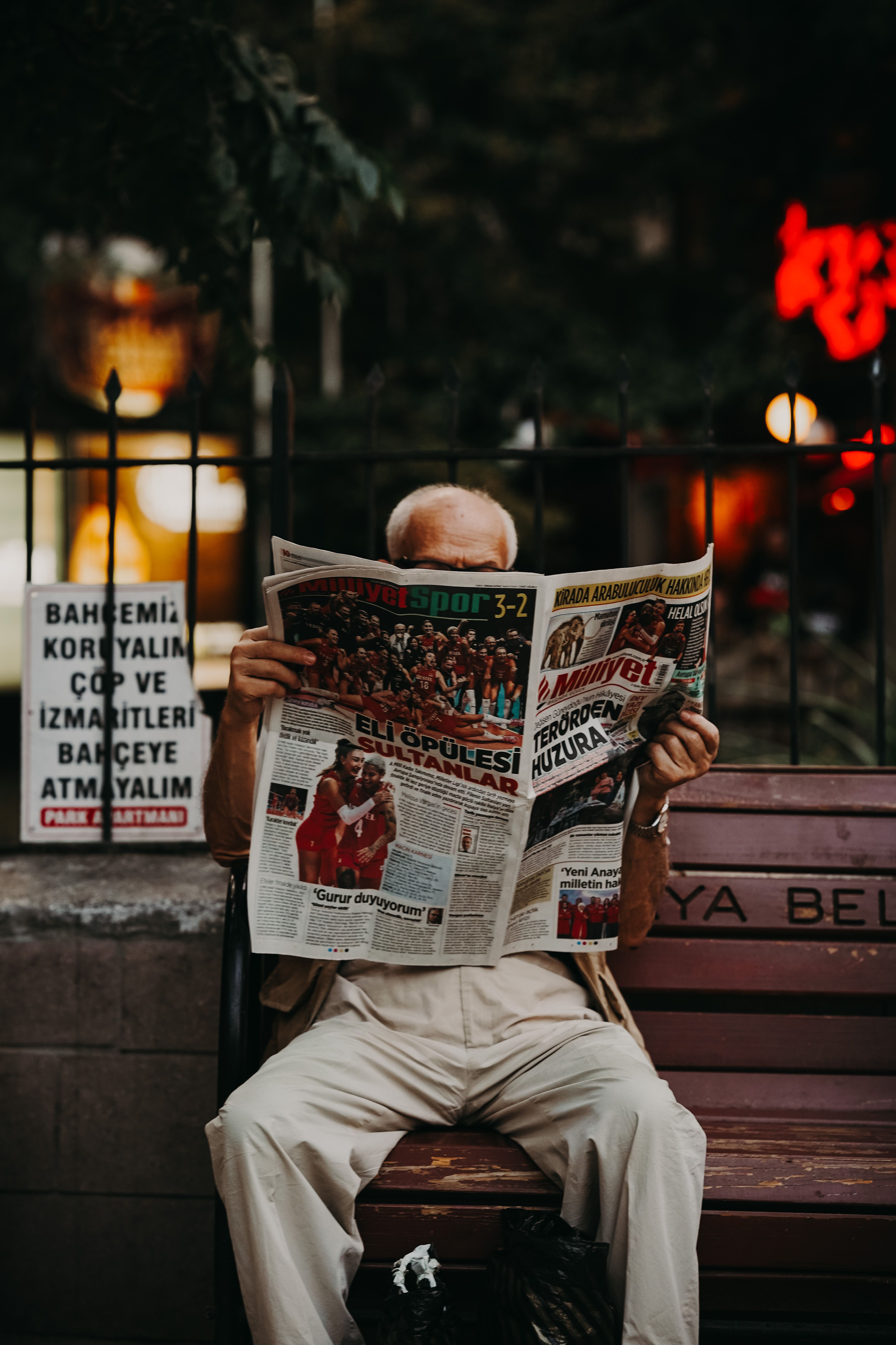 Man Sitting on Bench and Reading Newspaper · Free Stock Photo