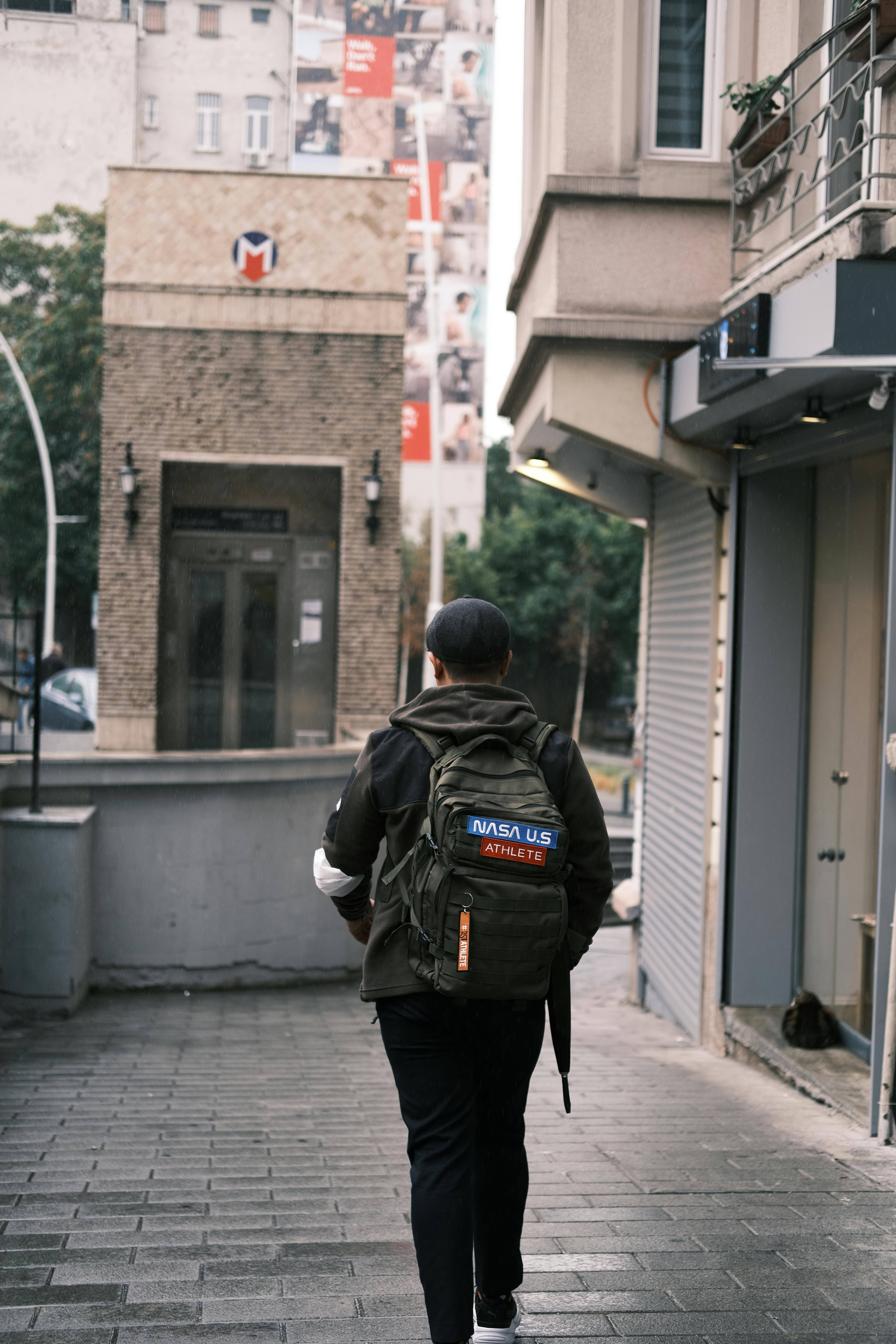 Back View of a Man with a Backpack on the Sidewalk · Free Stock Photo