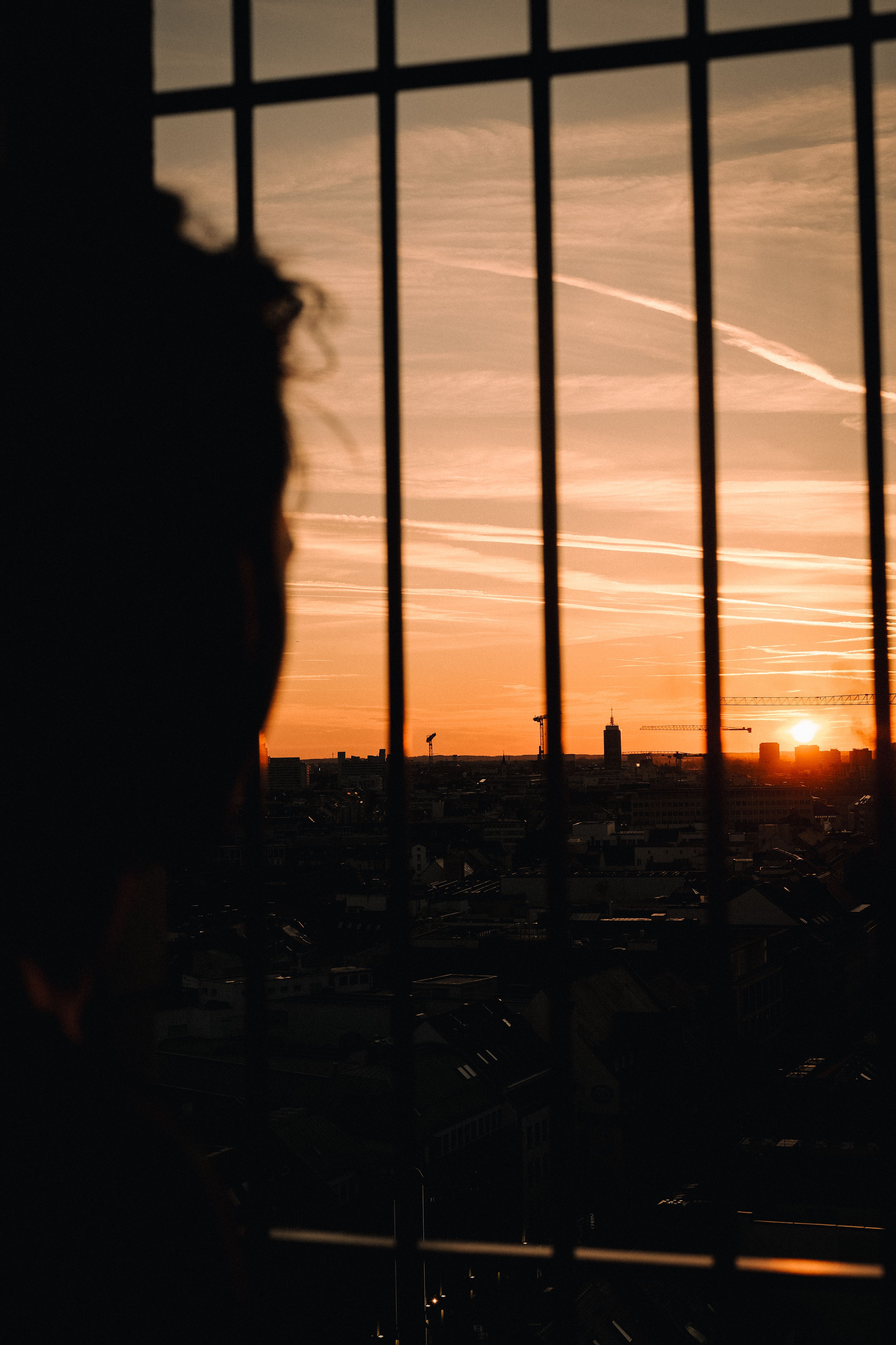 Woman Looking at Sunrise over the City from a Window · Free Stock Photo