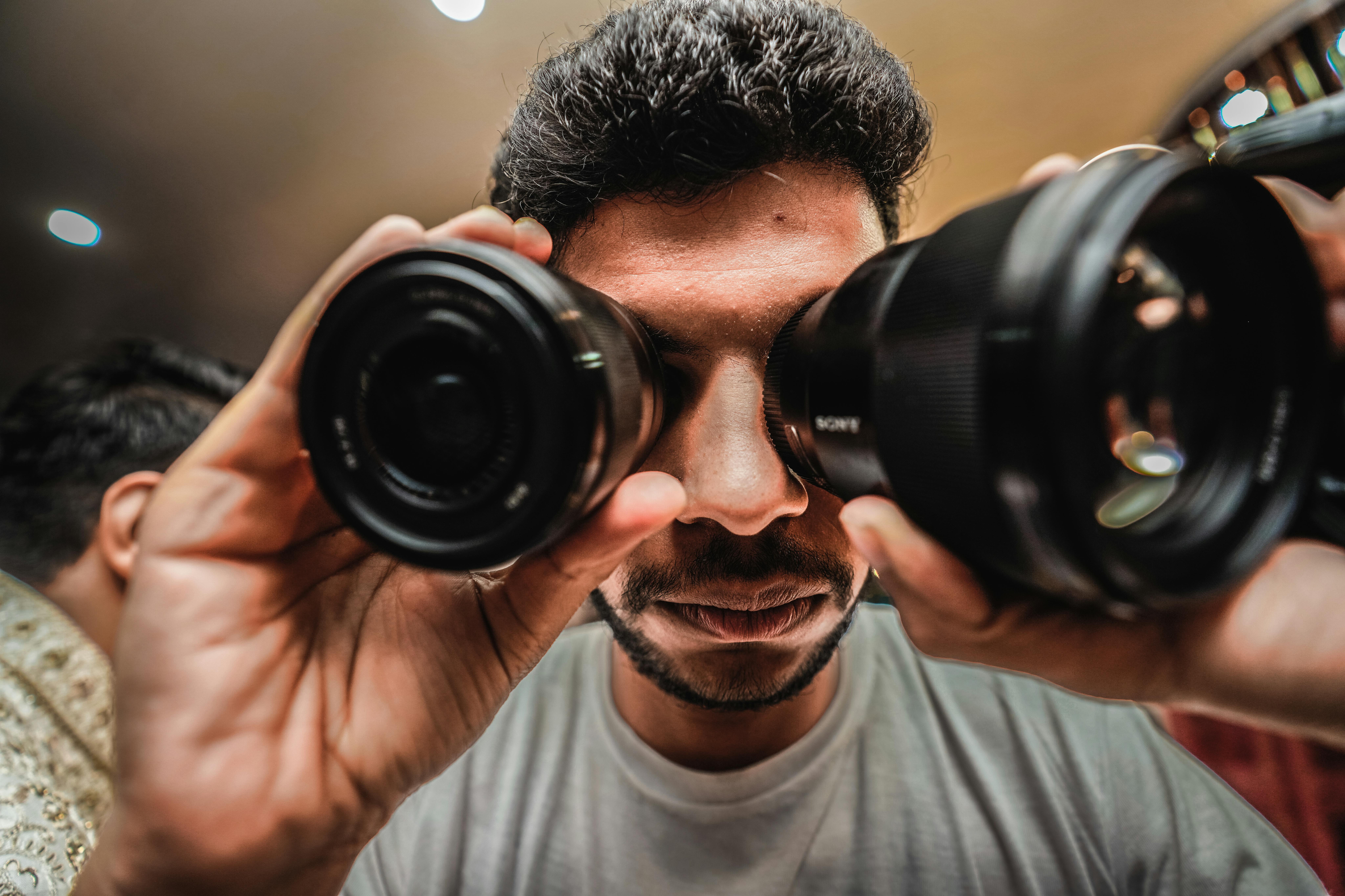 Portrait of Man Holding up Camera Lenses to his Face · Free Stock Photo