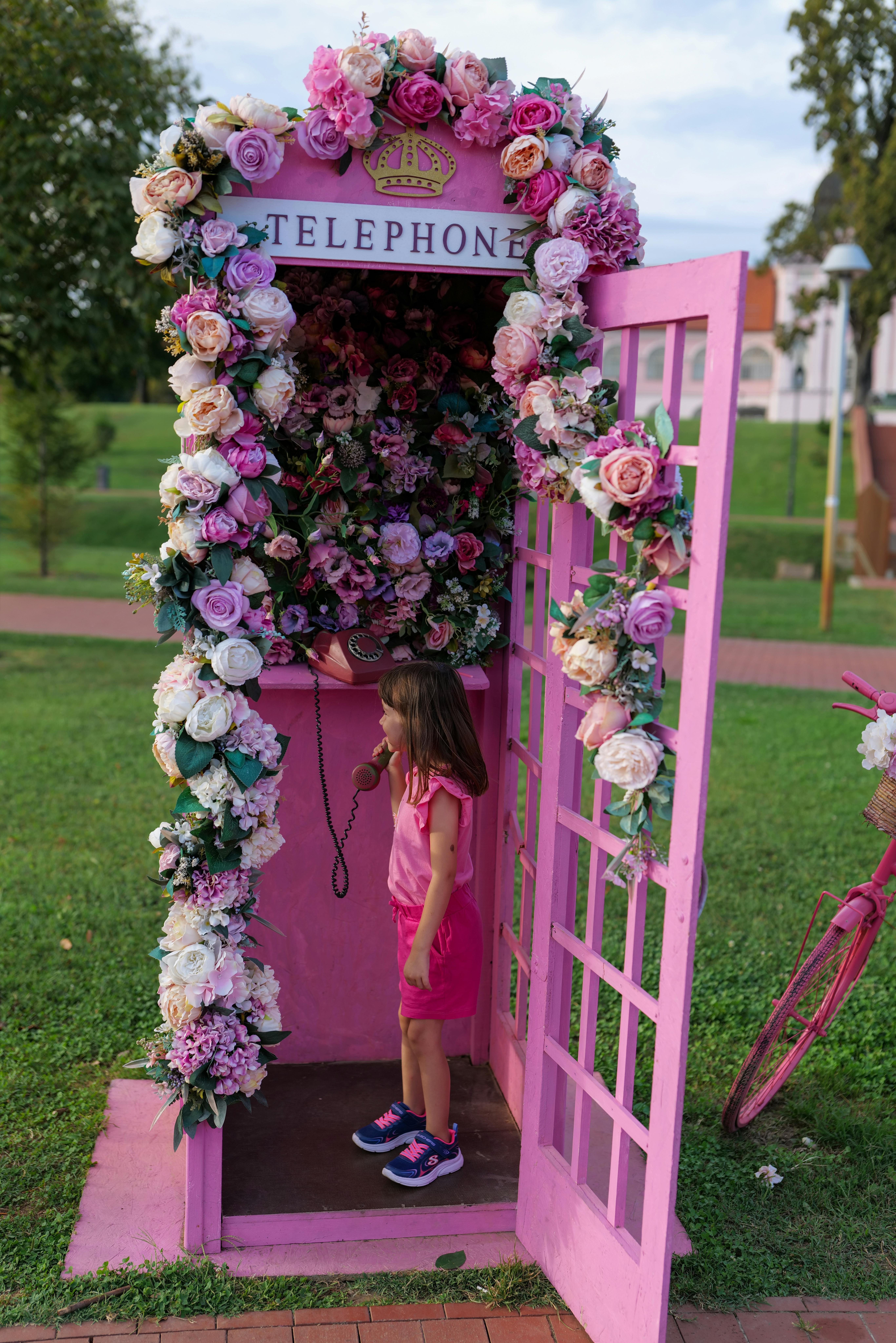 Girl in Pink Telephone Booth with Flowers · Free Stock Photo