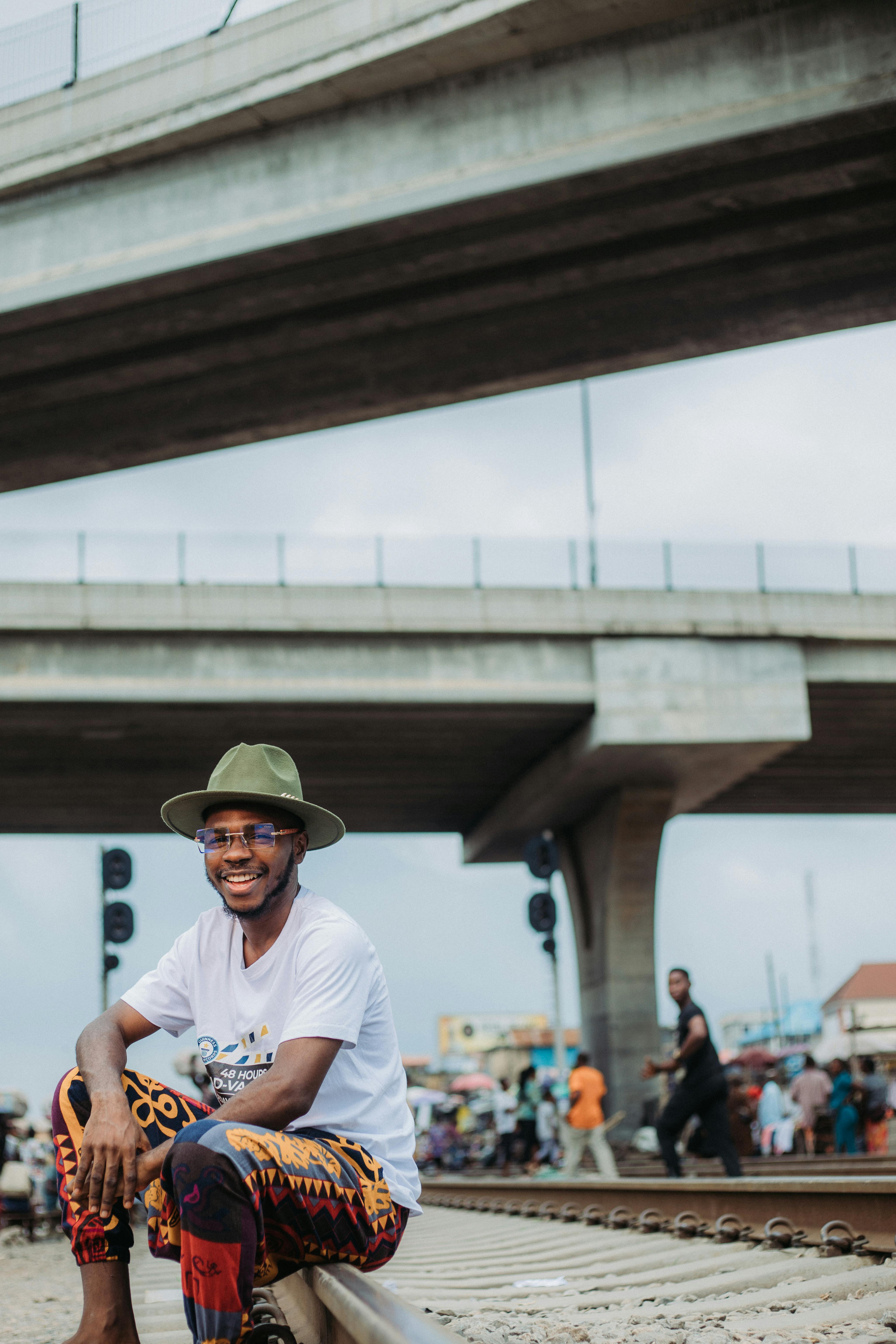 Smiling Man Sitting on Train Tracks · Free Stock Photo