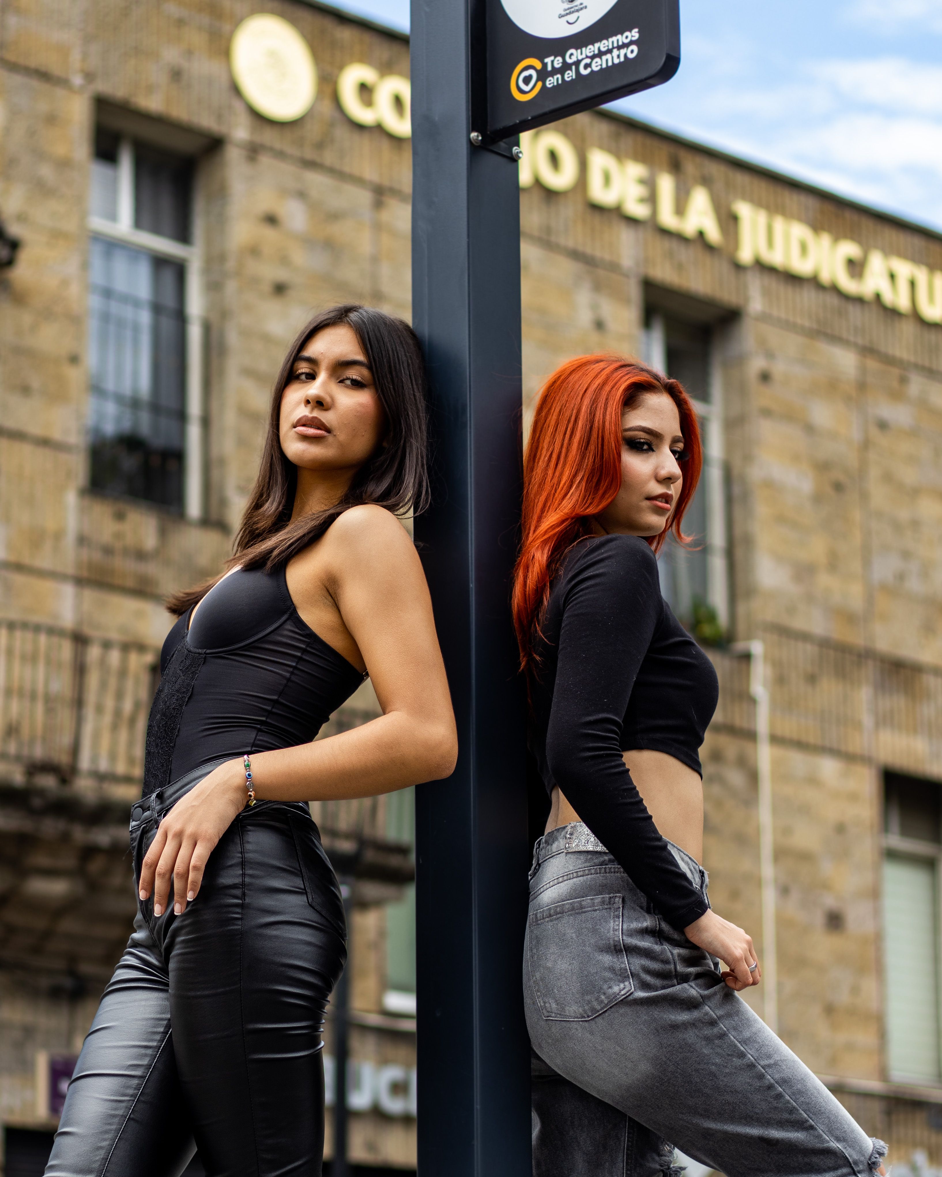 Two Female Models Leaning on a Directional Sign · Free Stock Photo